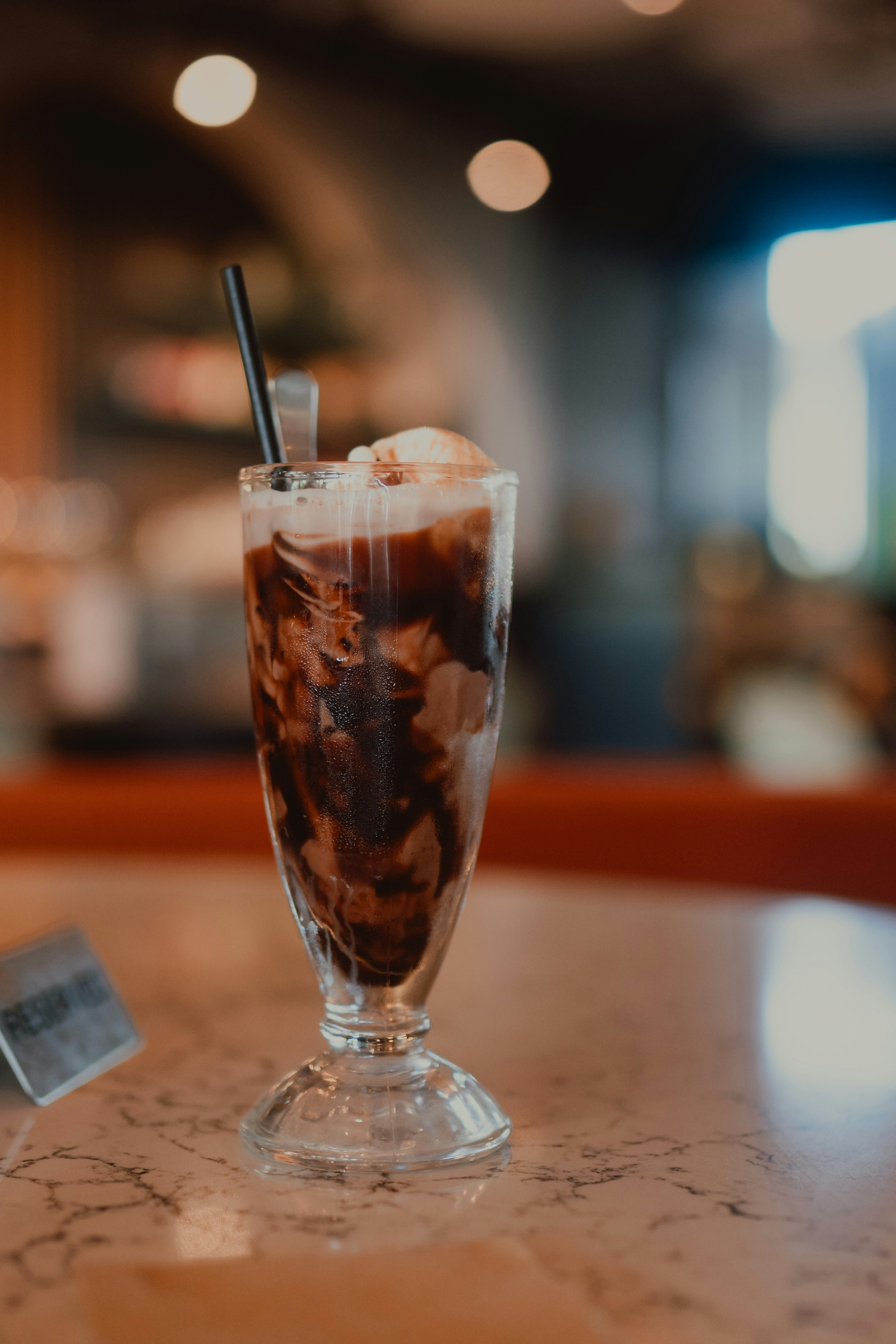 A chocolate sundae with ice cream in a tall glass.