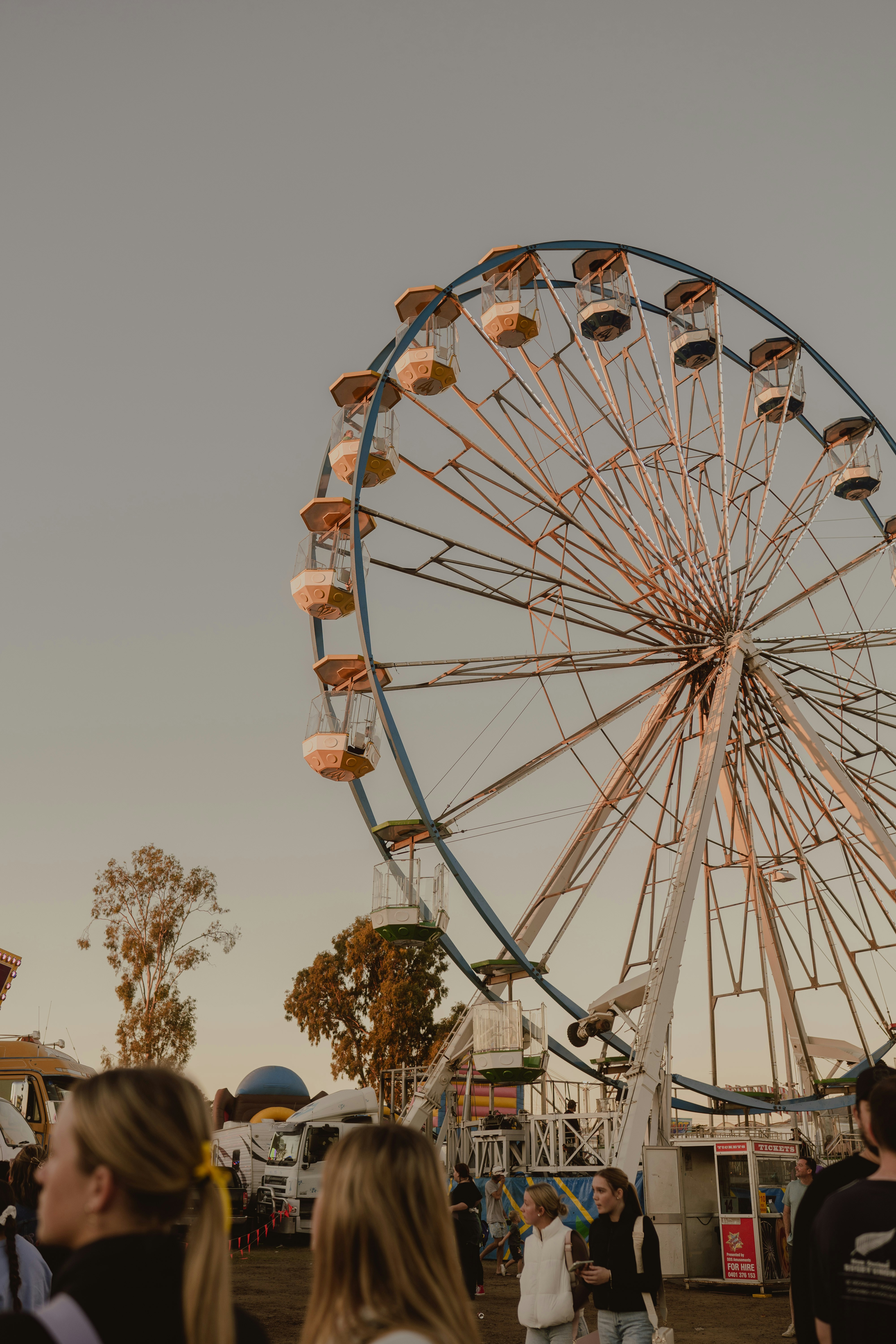 Ferris Wheel at Dusk: A Carnival Scene Framed by People