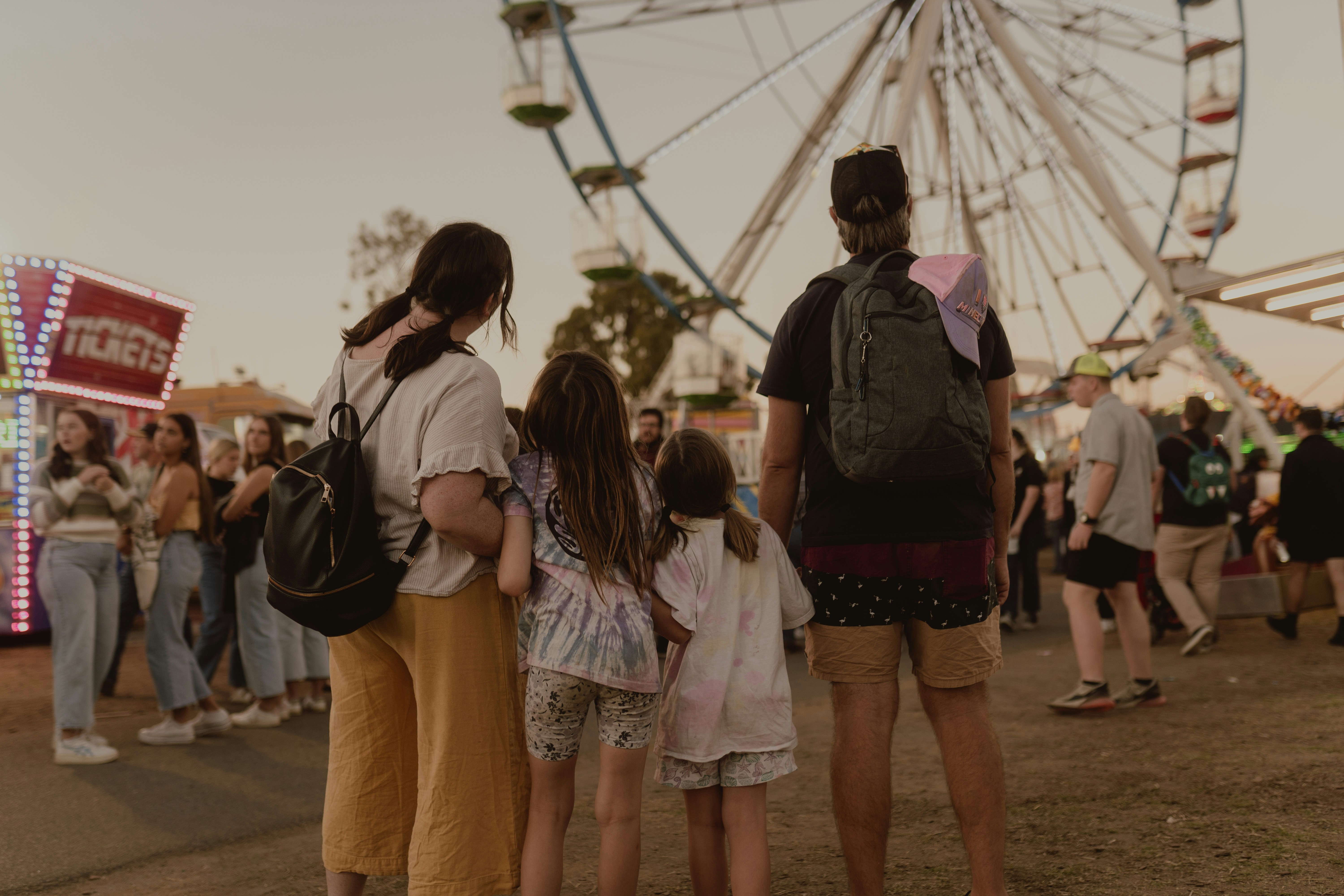 Family at a Sunset Carnival: A Gentle Crowd Leading Toward the Ferris Wheel