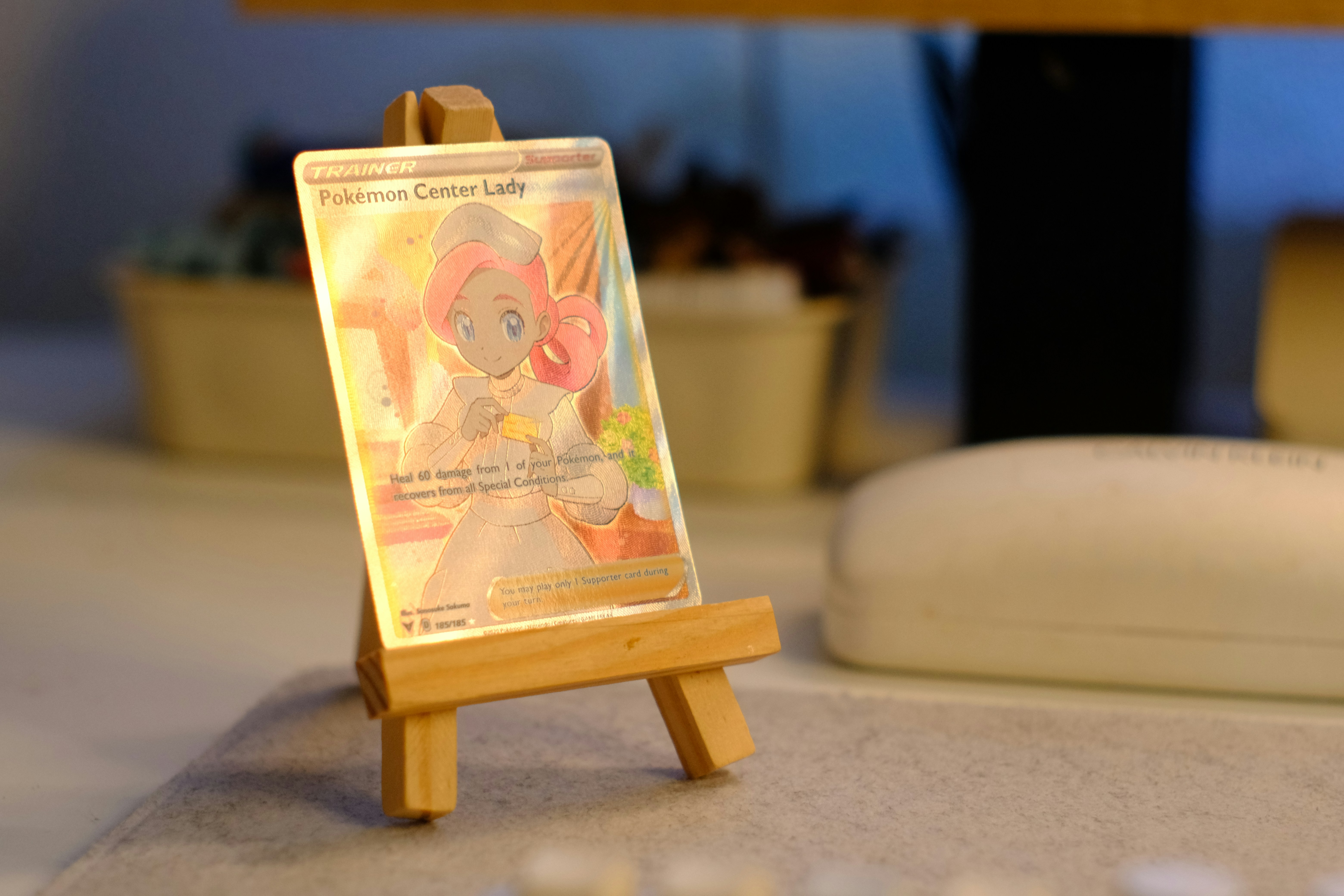 Holographic anime trading card on a miniature wooden easel.