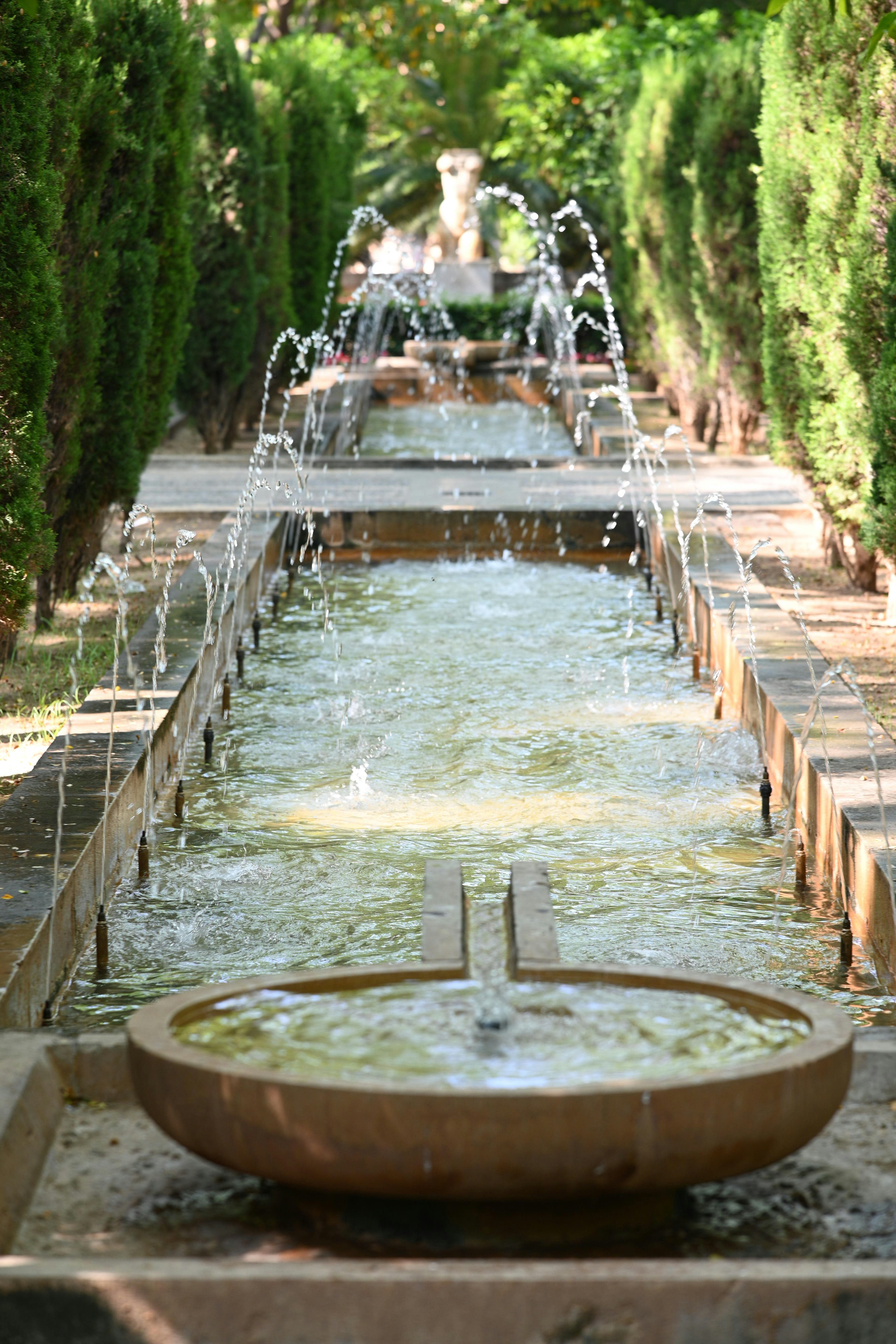 Beautiful tiered fountain surrounded by lush green trees.