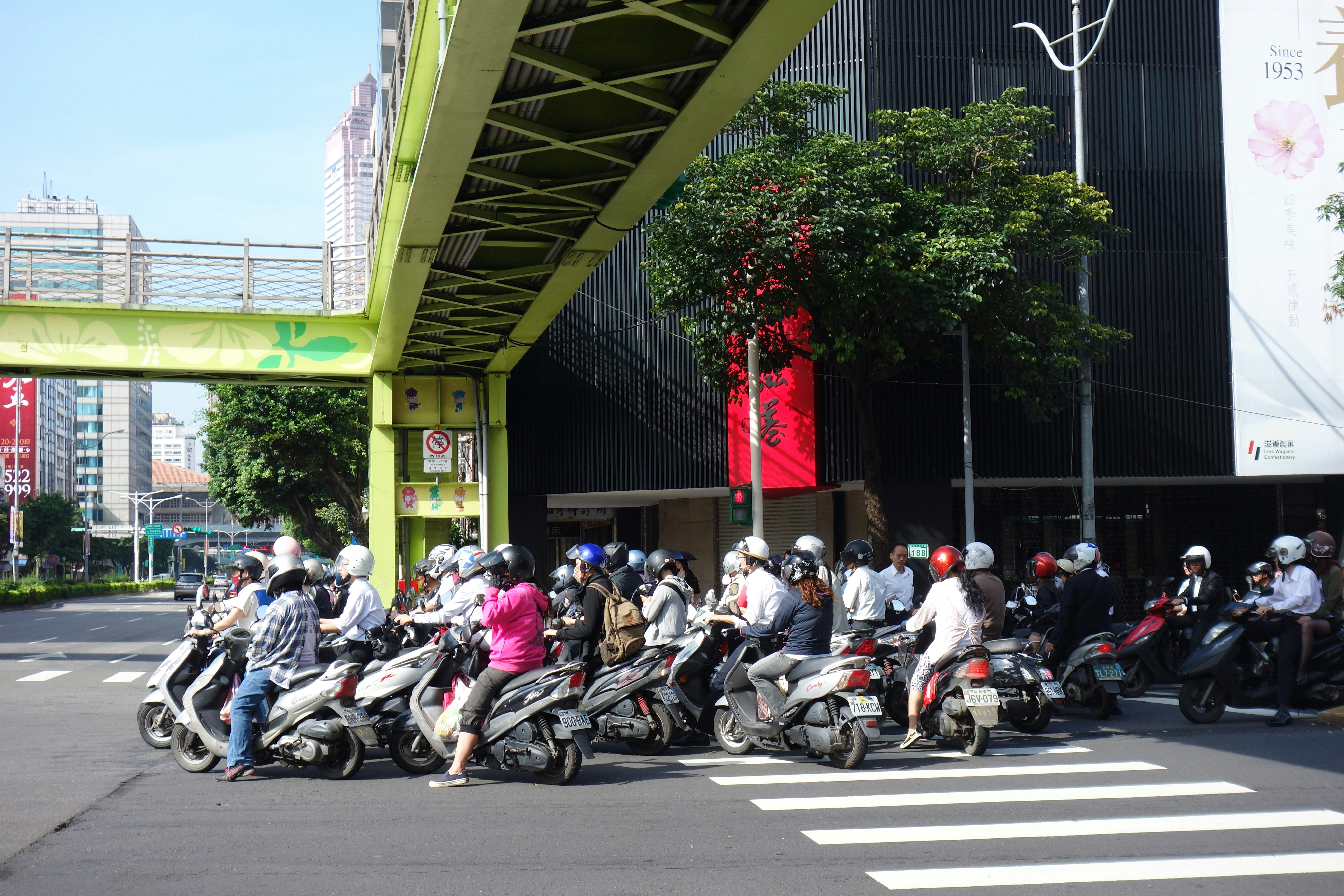 Scooter Armada at a City Crossing Under a Lime-Green Overpass