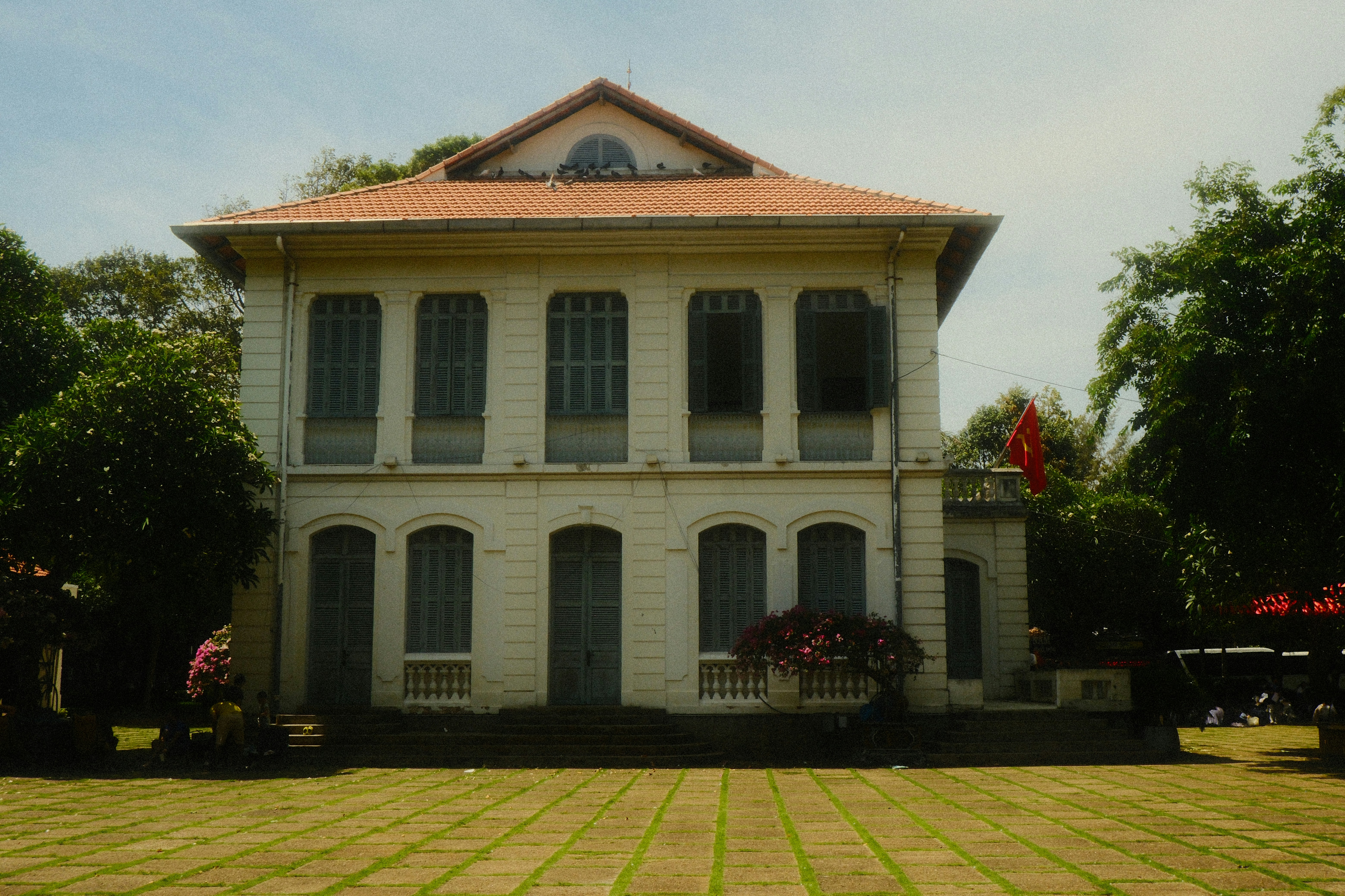 Old colonial manor framed by shadowed trees and a flag