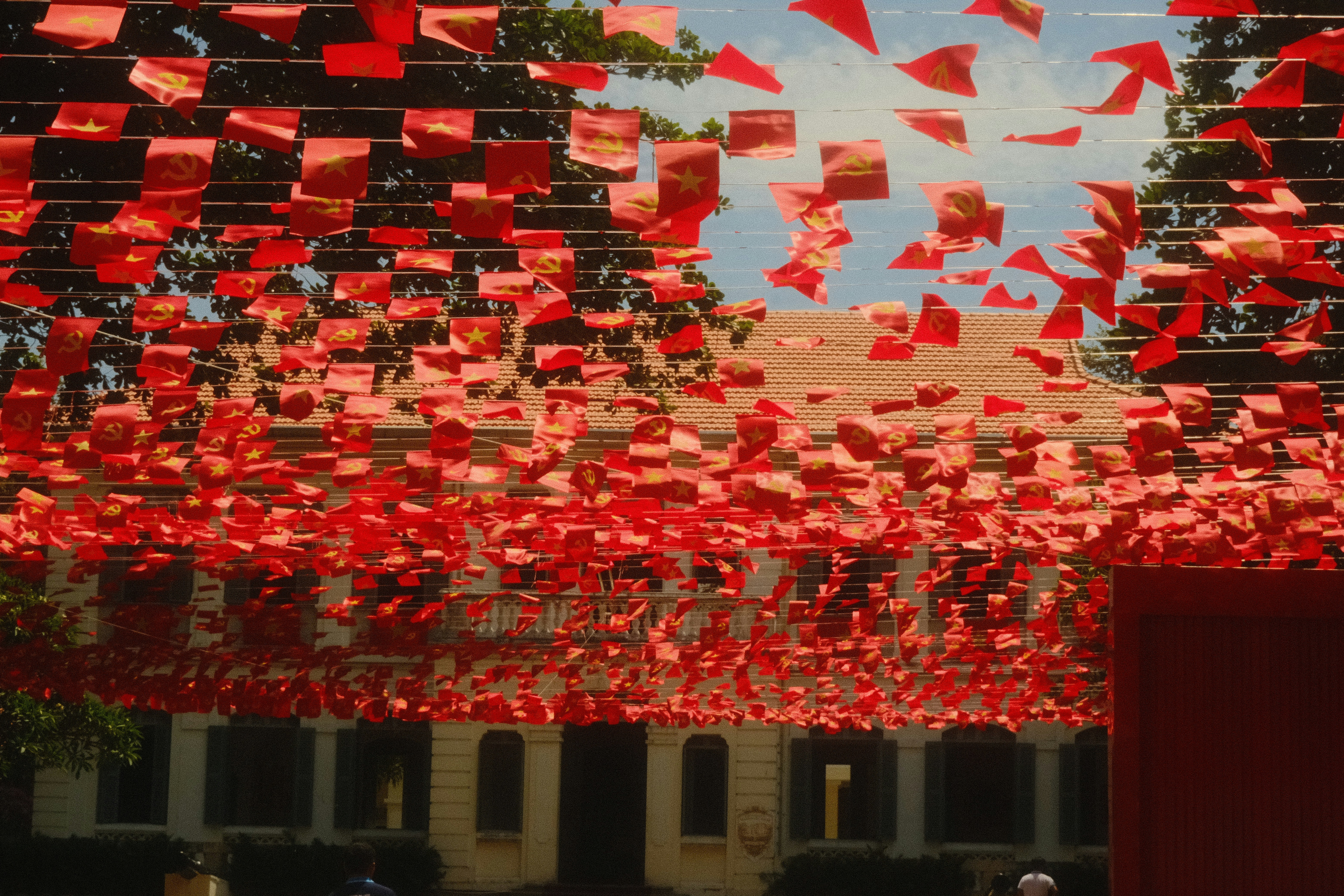 Red canopy of celebration: a sky full of banners over a quiet courtyard