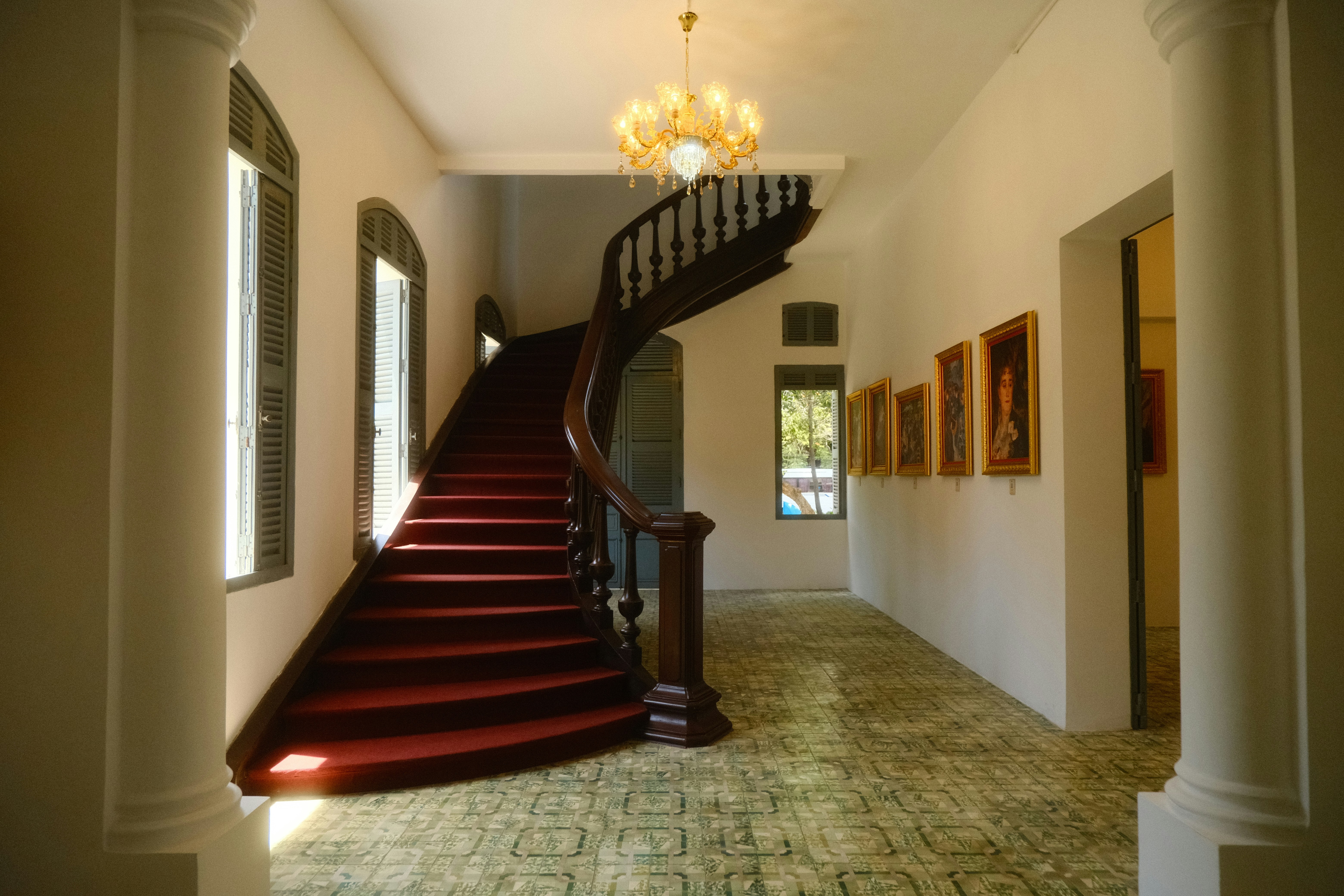 Historic building interior with grand wooden staircase and chandelier.