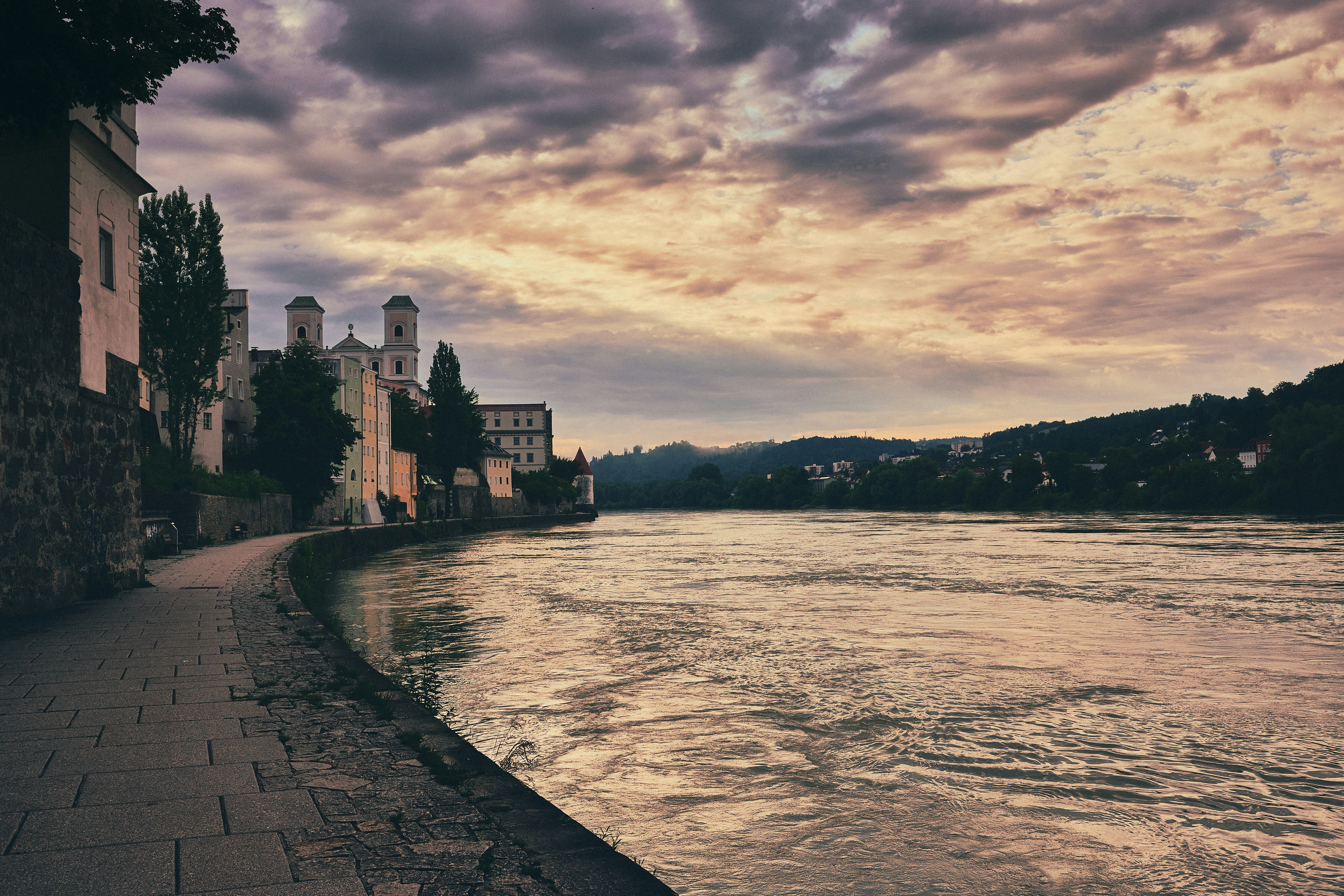 Evening along the riverside: stone walkway, historic fortifications, and a glow on the water