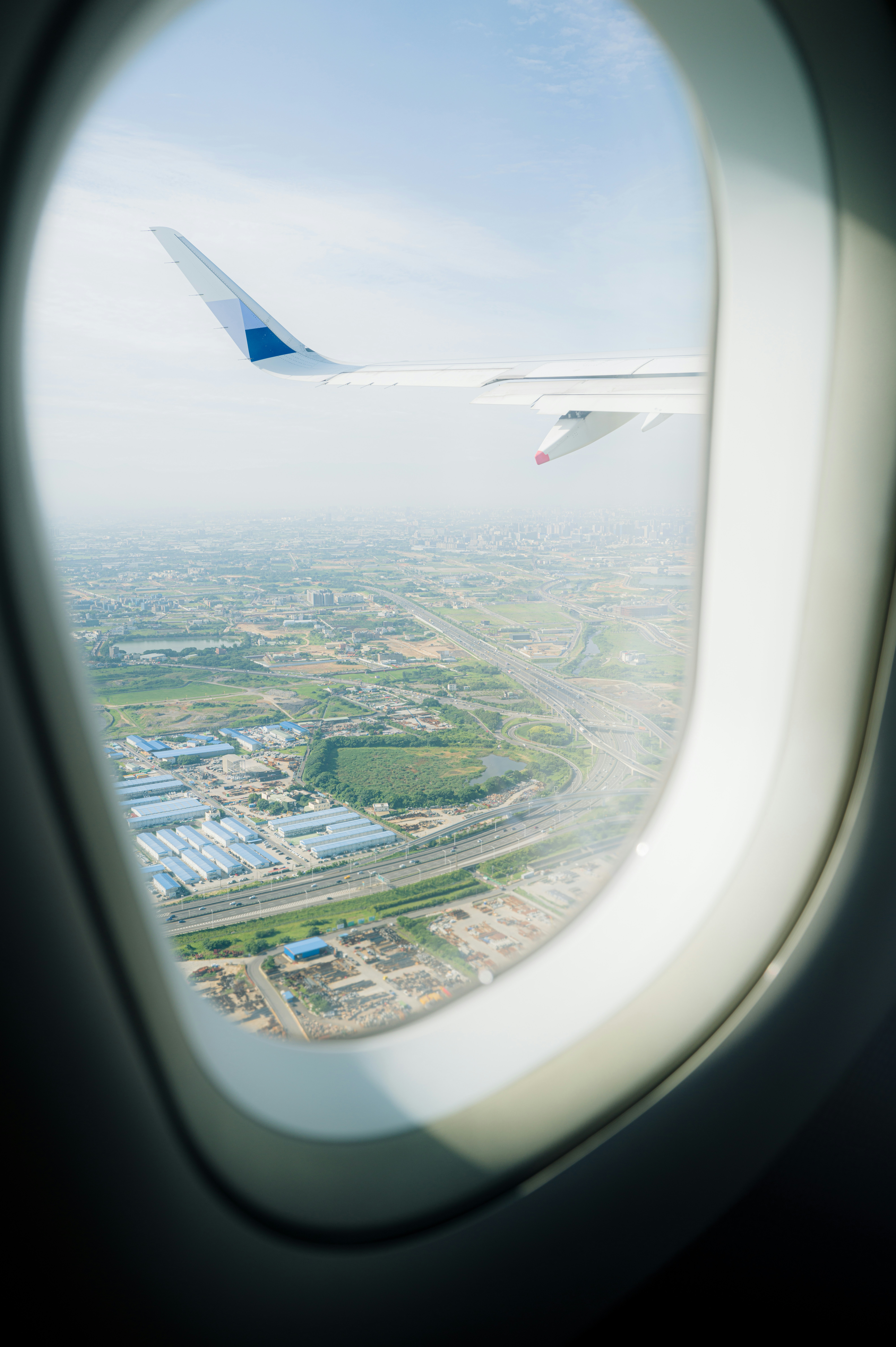 Airplane wing and city view from a window.