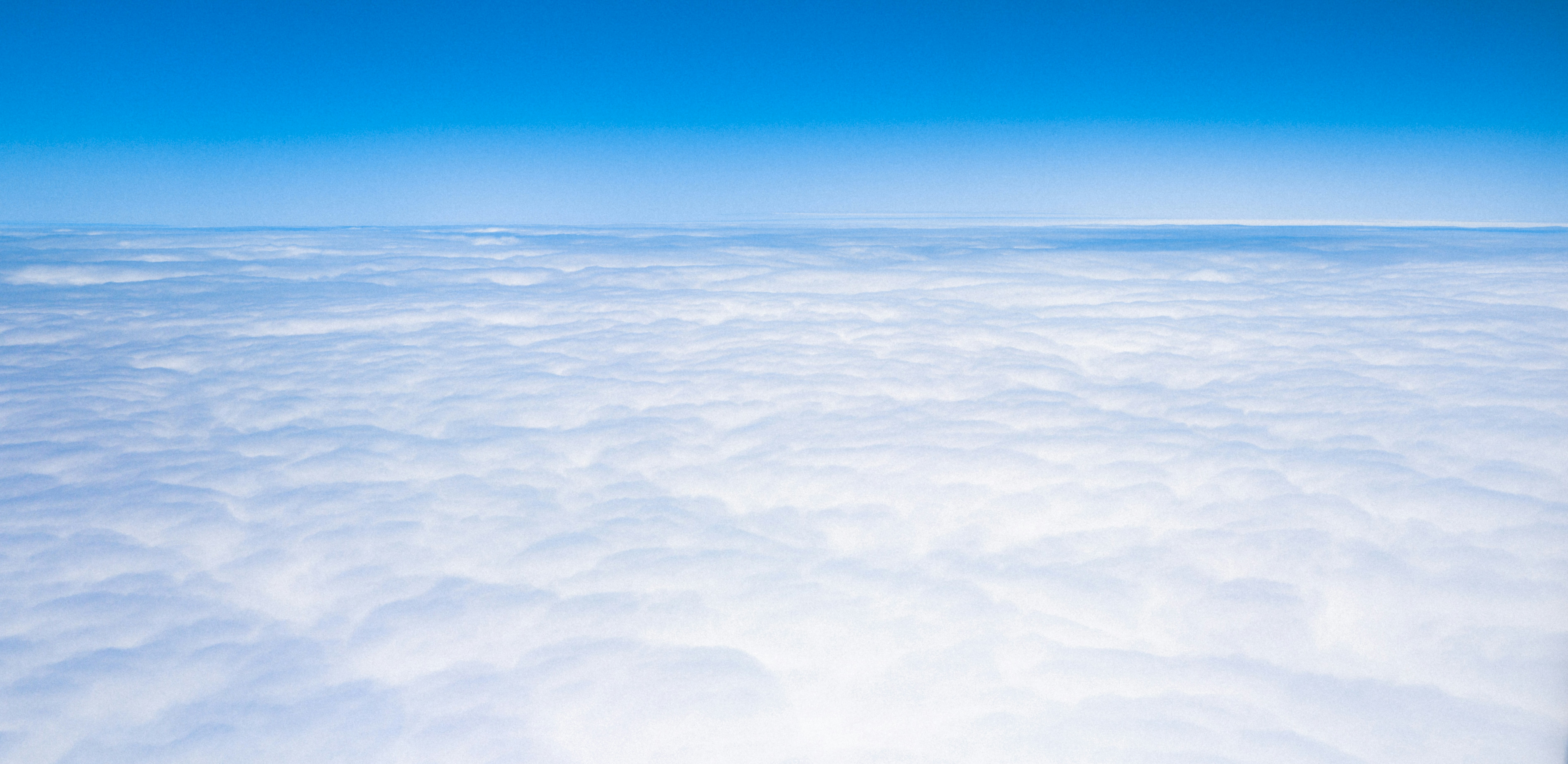 Vast white clouds under a clear blue sky from above.
