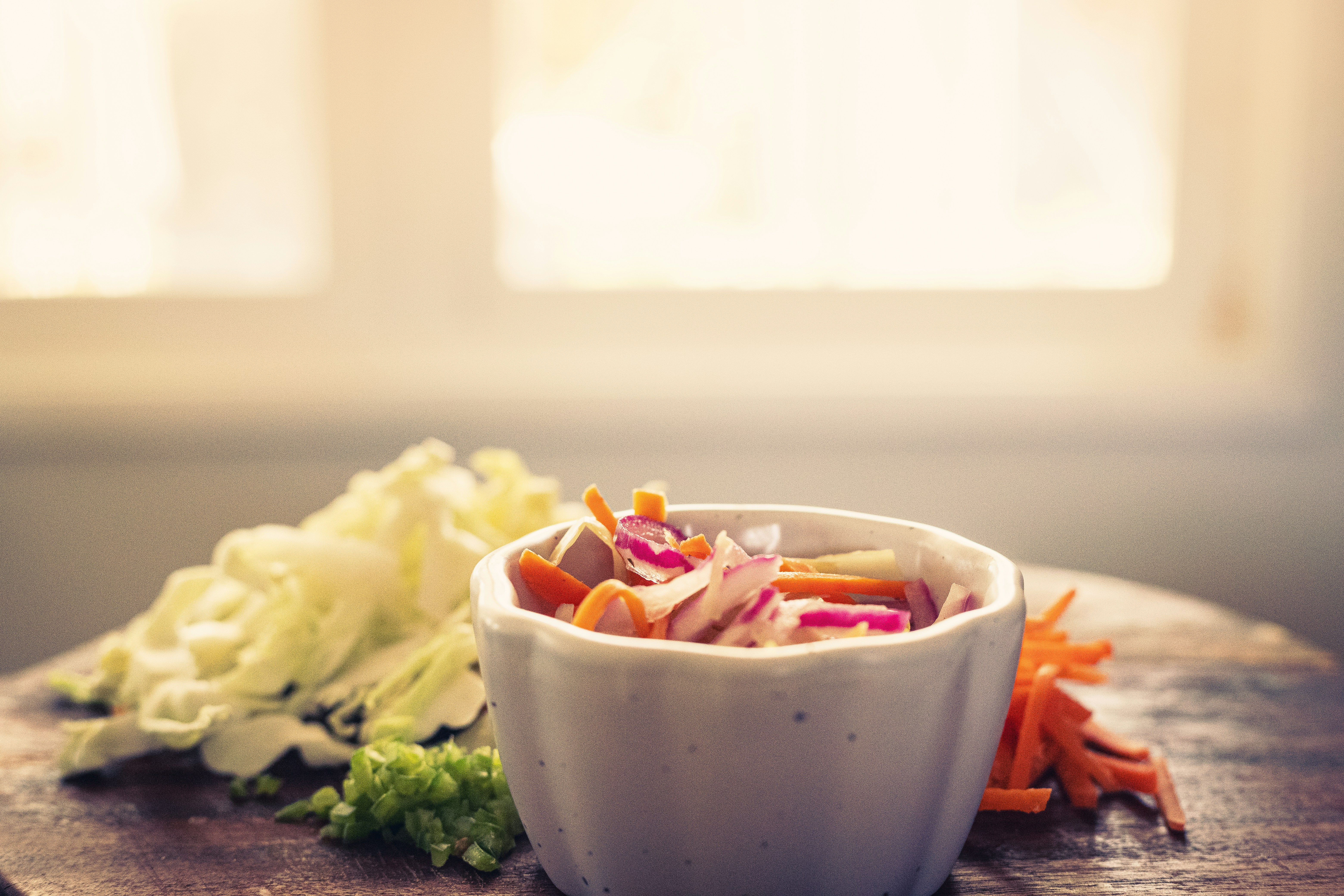 Centered Bowl of Fresh Salad with Shredded Vegetables on Wooden Table