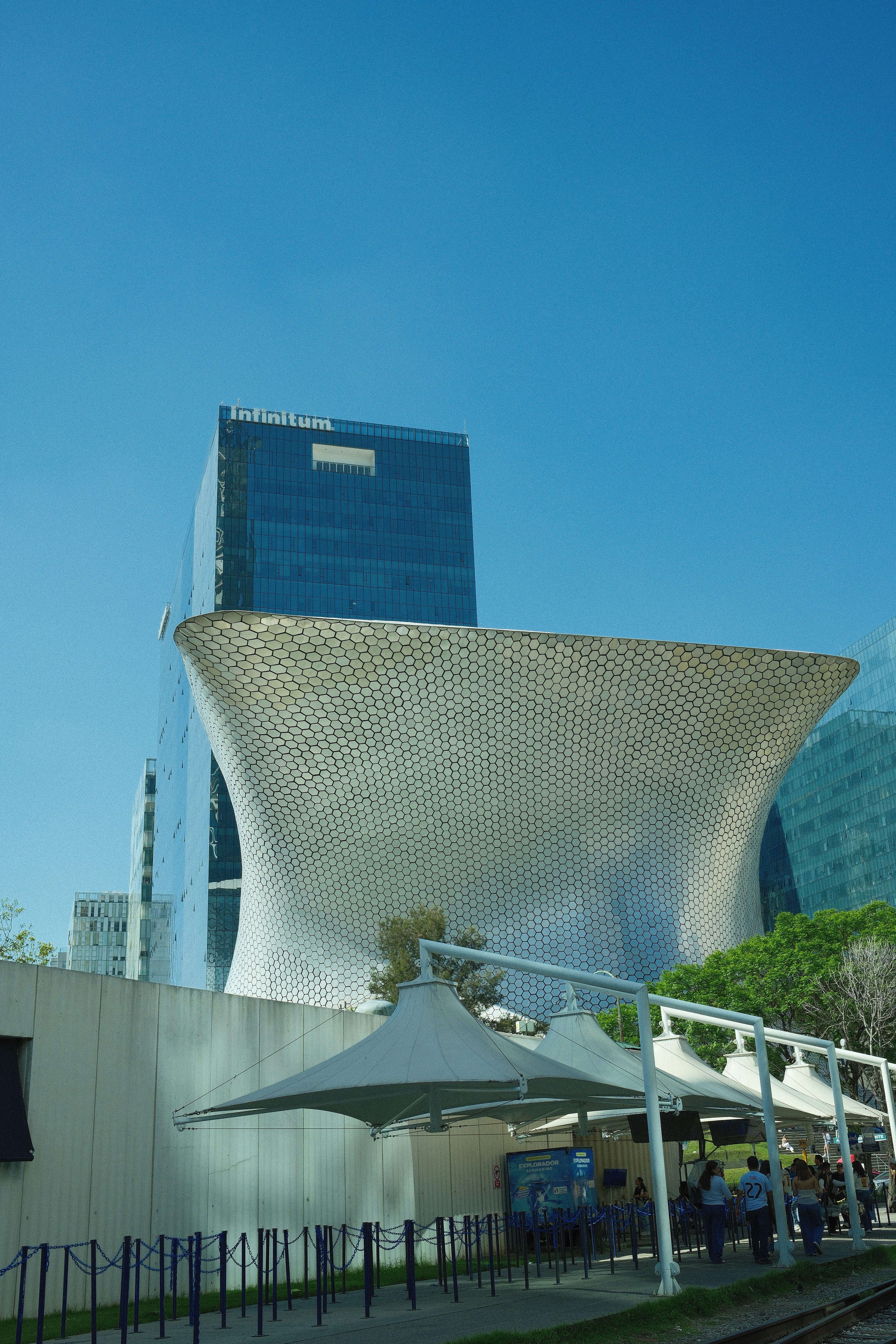 Iconic soumaya museum and skyscraper under a bright blue sky.