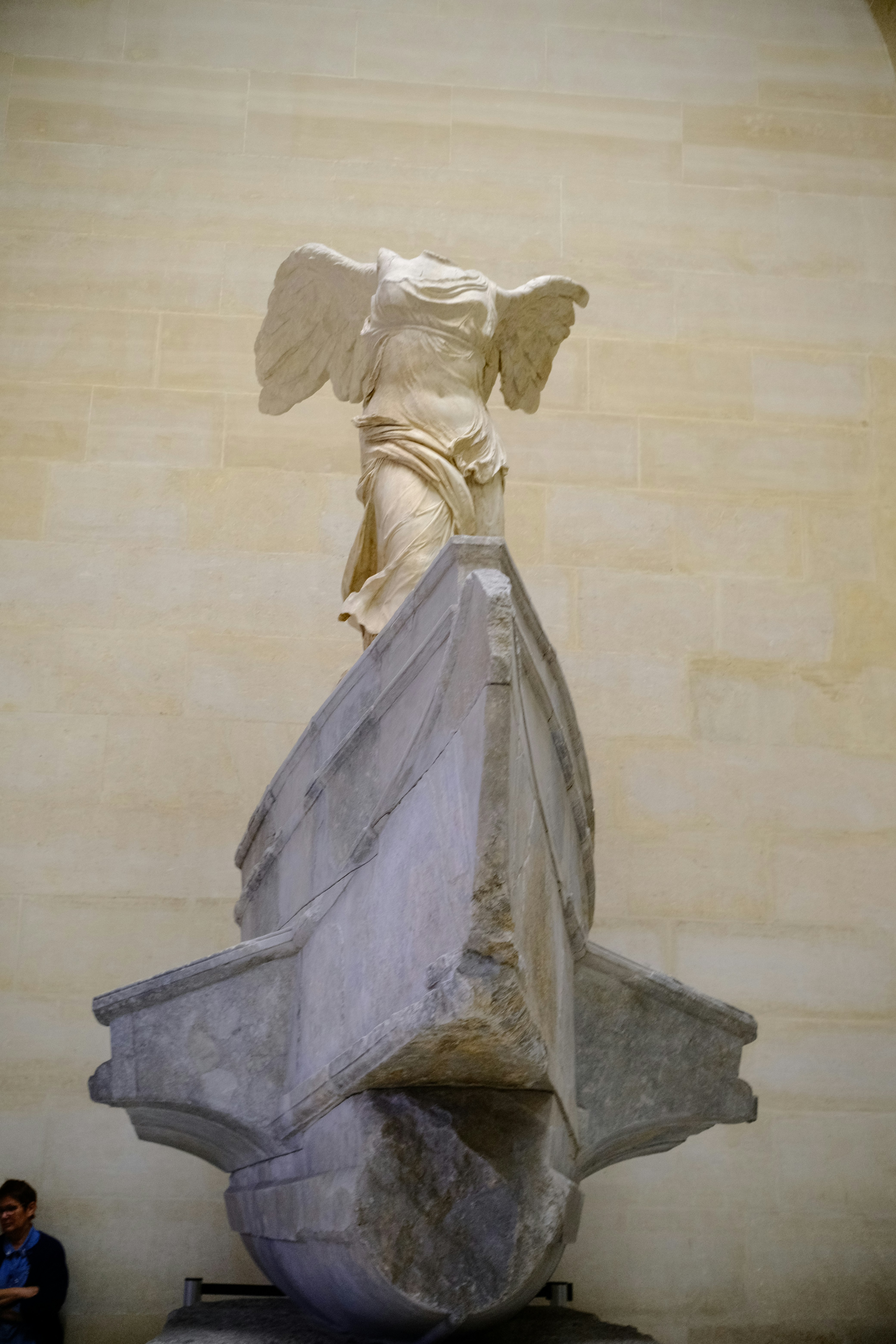 Winged statue on a stone prow underarched by warm stonework