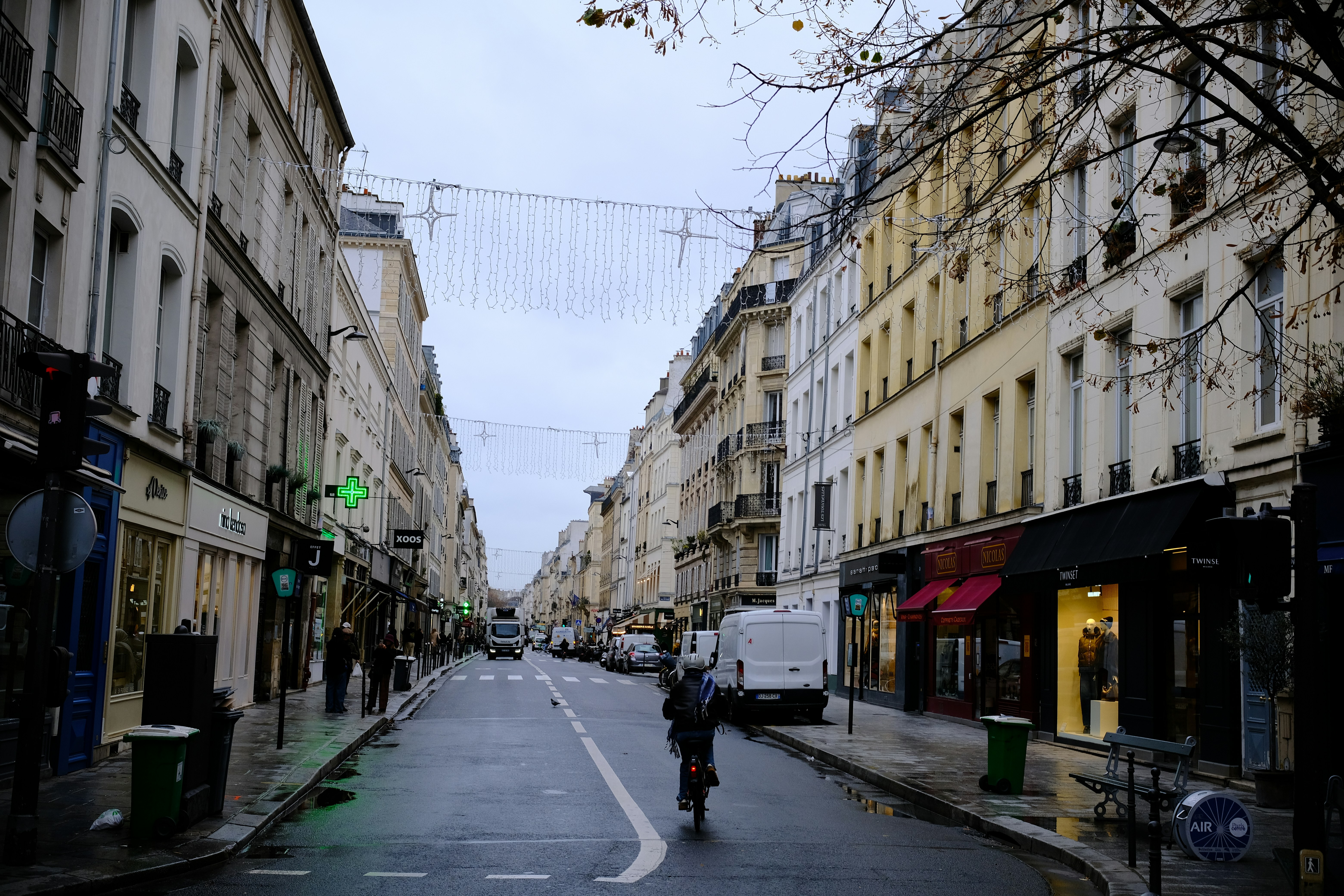 Rainy Rue: A cyclist navigates a Parisian boulevard under festive lights