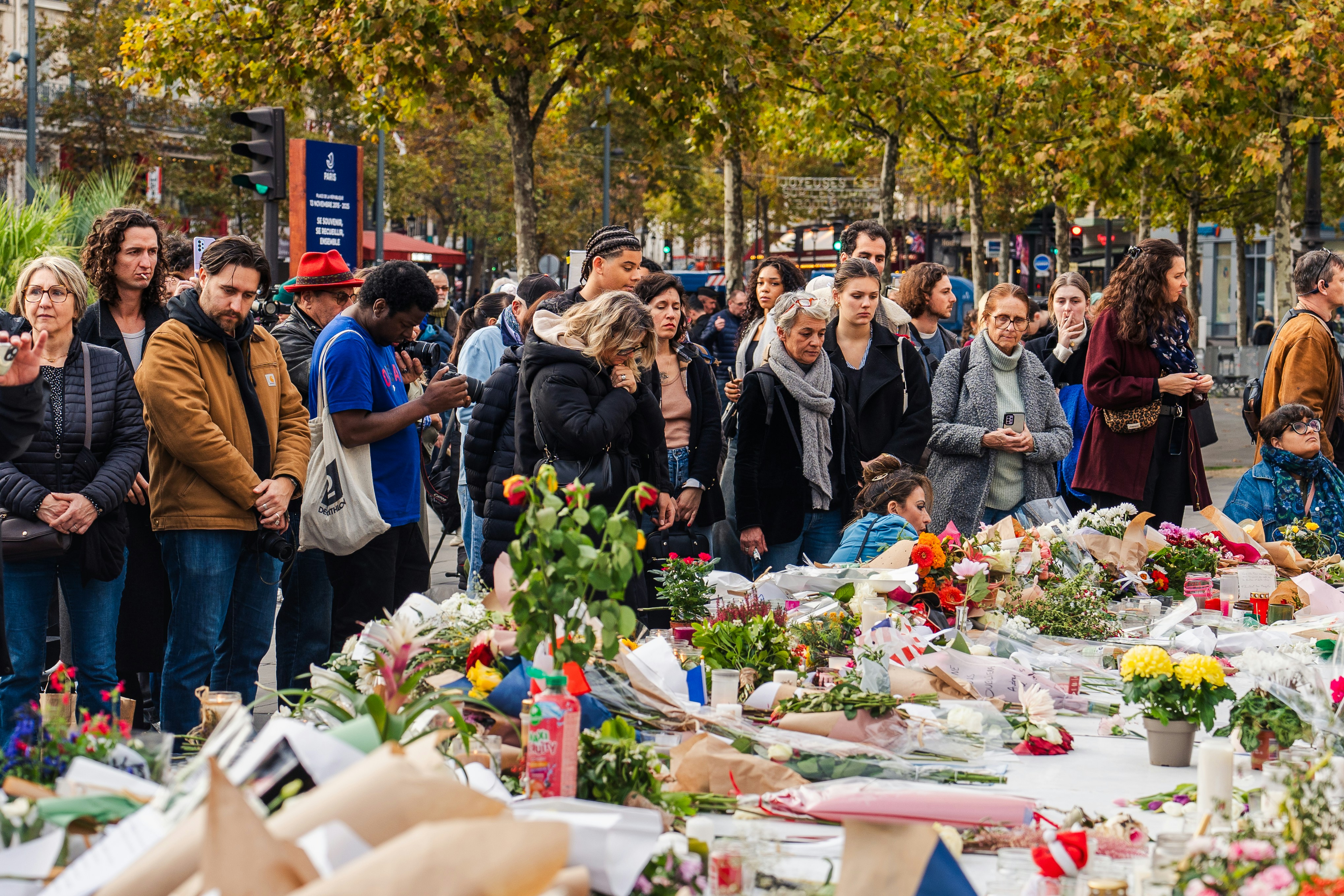 A Quiet Vigil: People Gather Around a Memorial Table of Flowers