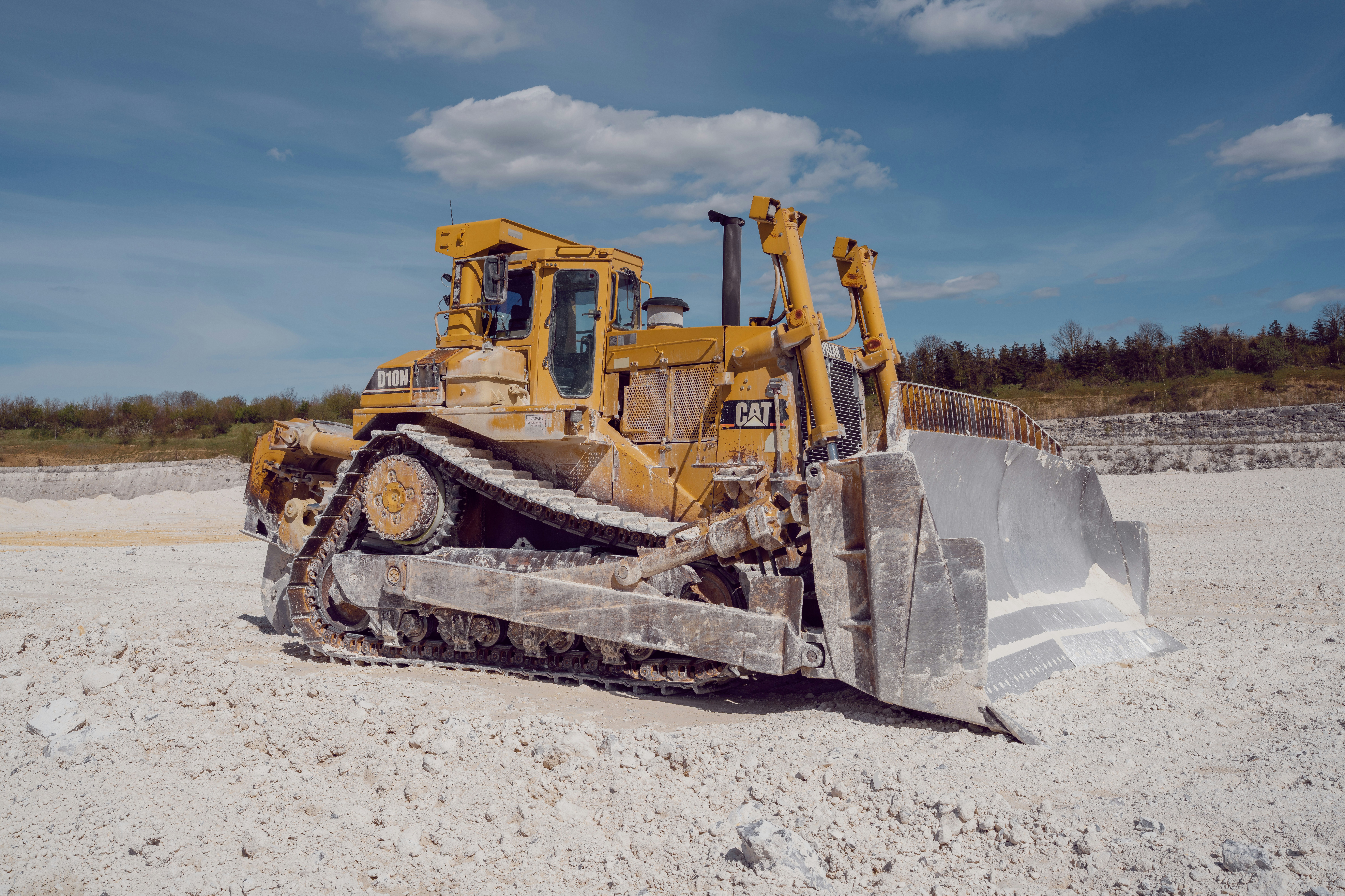Yellow behemoth on dusty plain: a bulldozer rests under noon sun