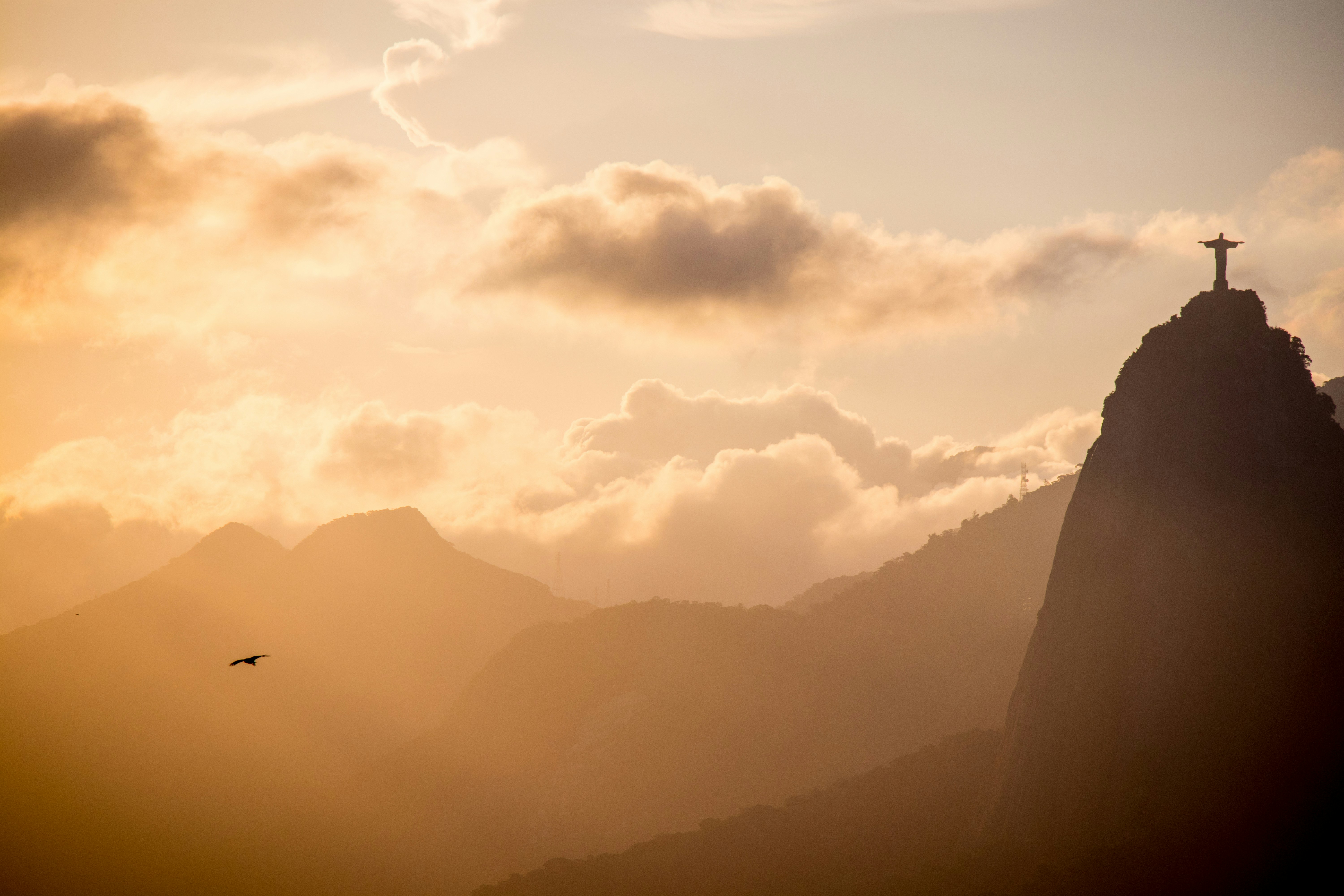 Silhouette of christ the redeemer and mountains at golden hour.