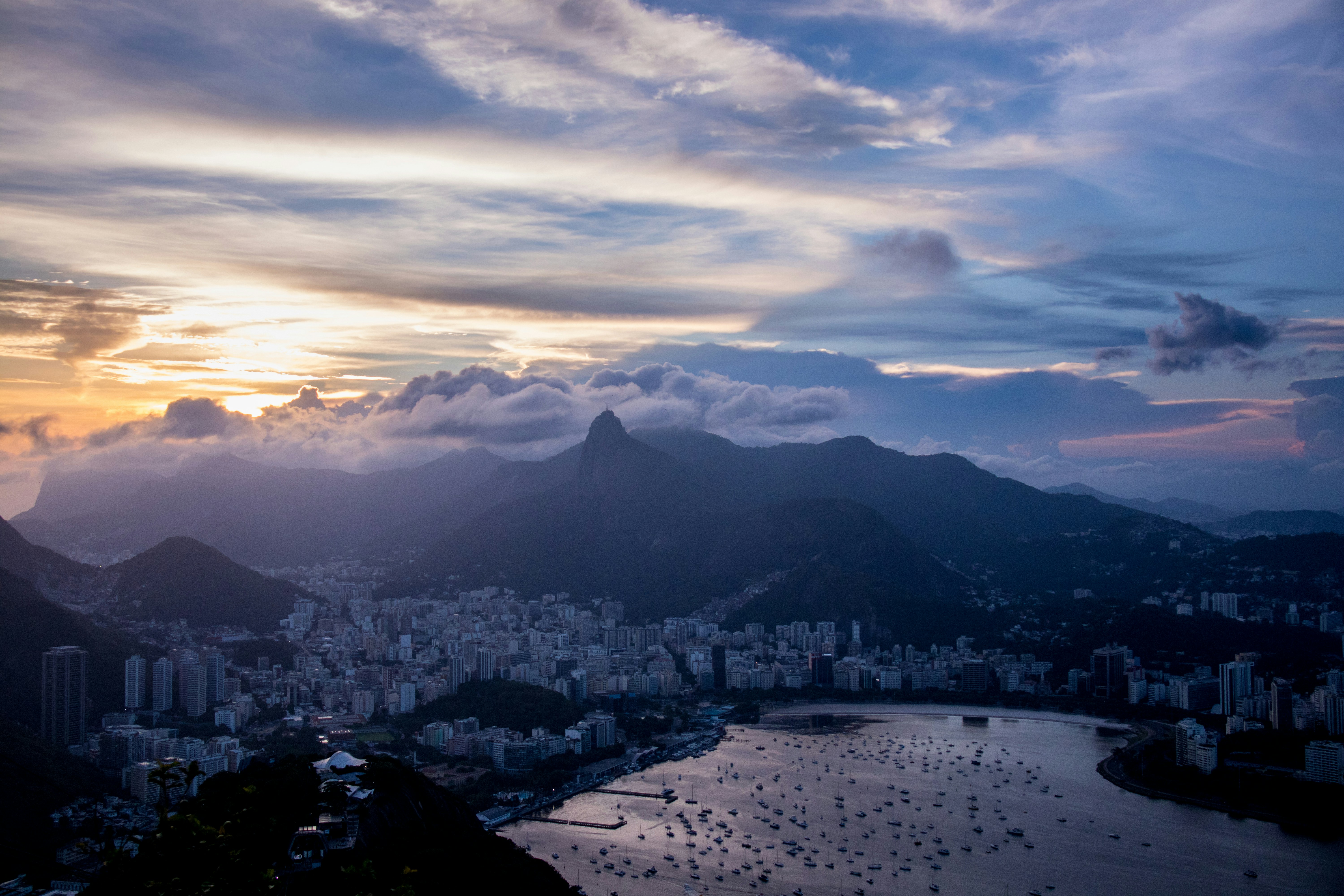 City, bay, and mountains under a dramatic sunset sky.