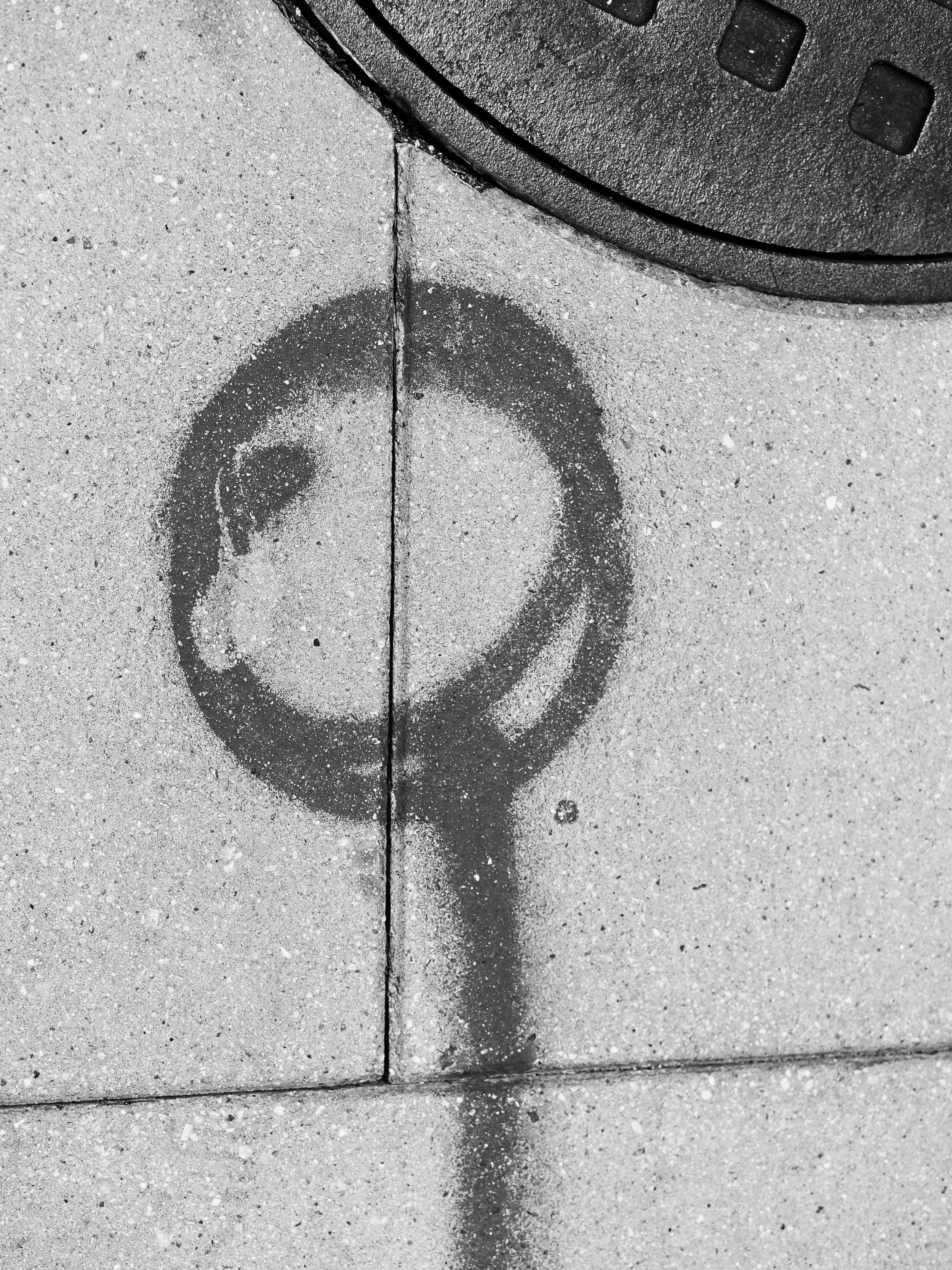 Shadowed Circle: A Street-stained Manhole Stencil on Concrete