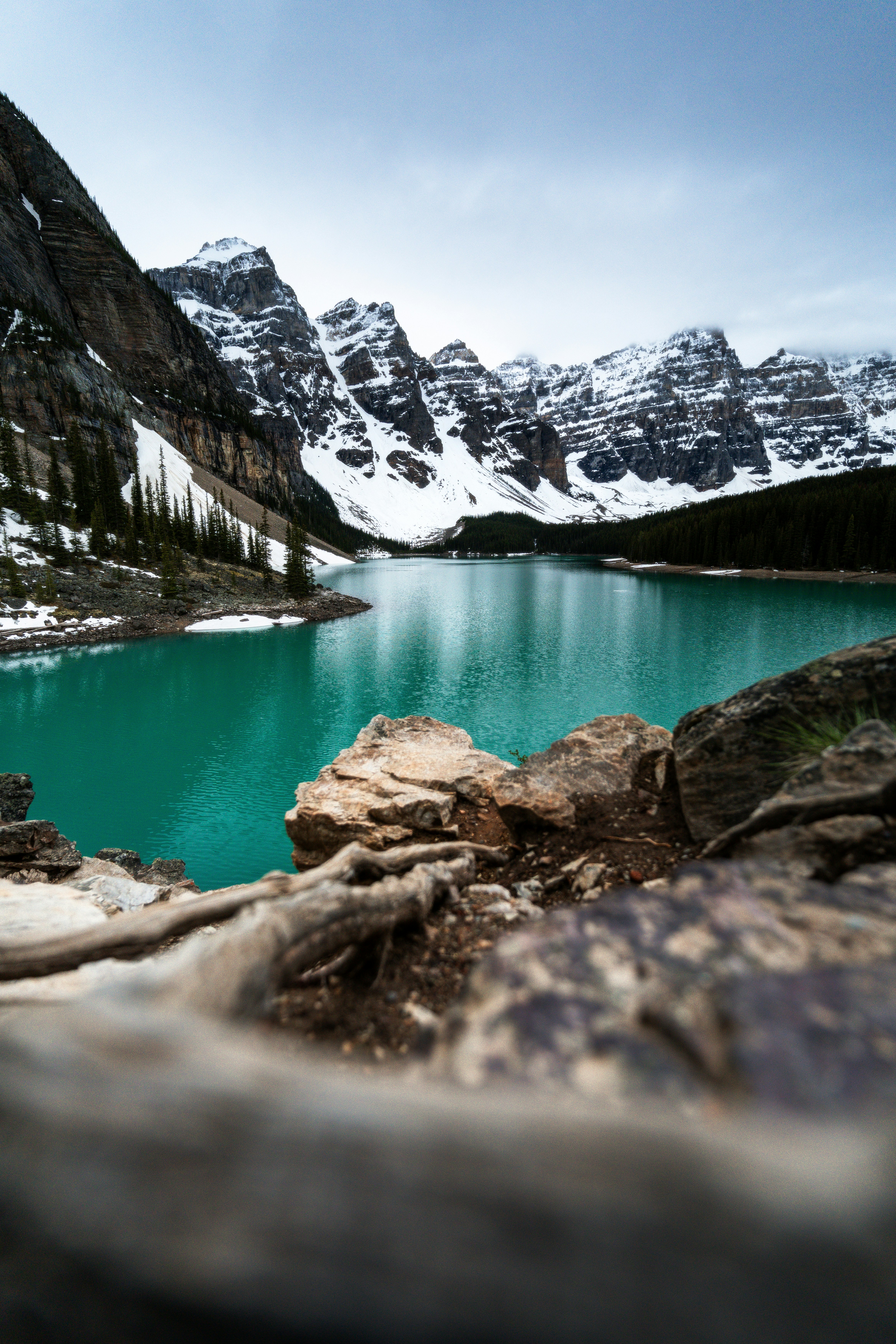 Serene turquoise lake framed by snowy mountains and rocks.