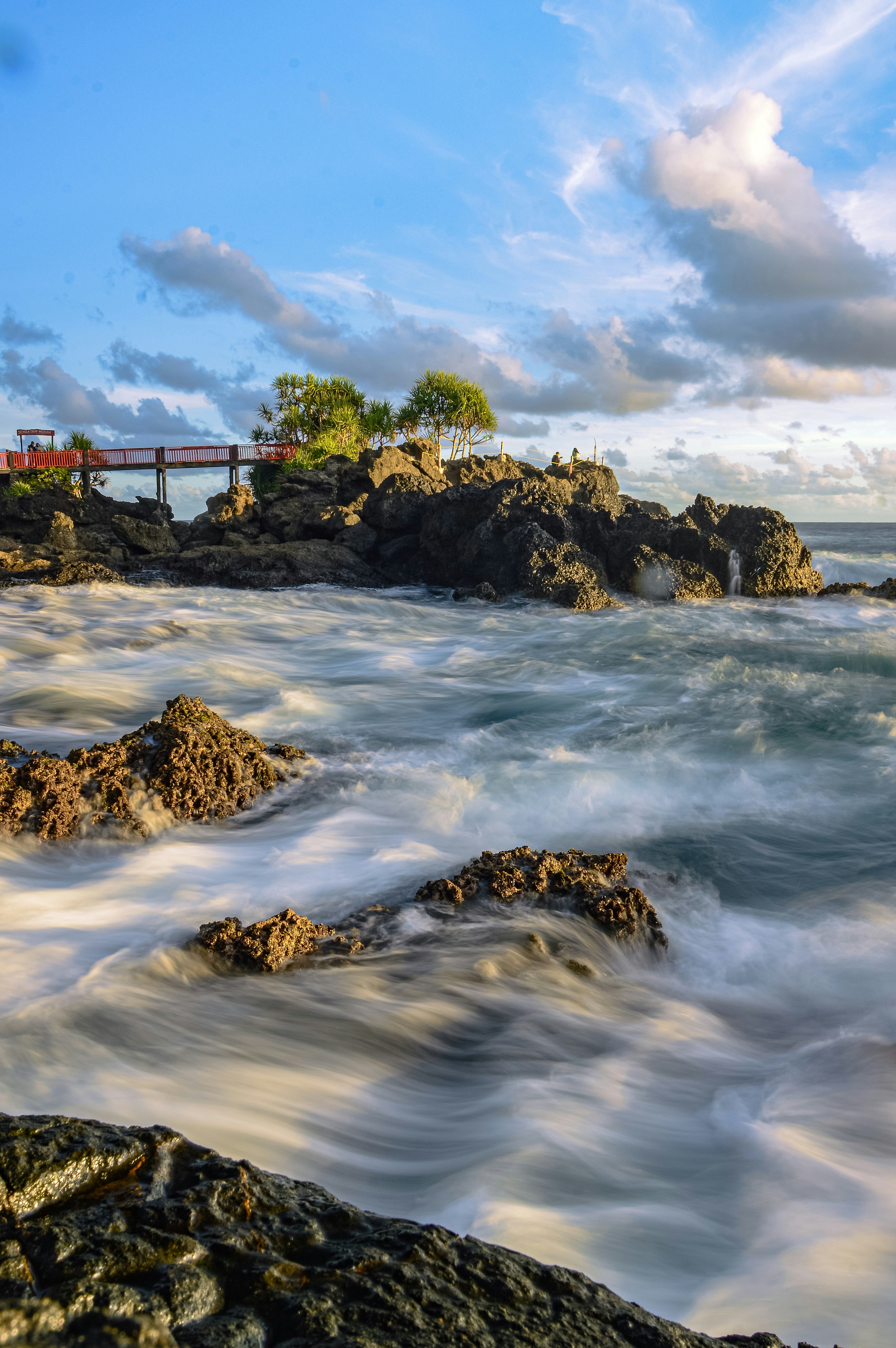 Sunlit Ledge: Waves Brush Against Jagged Rocks Under a Skyscape