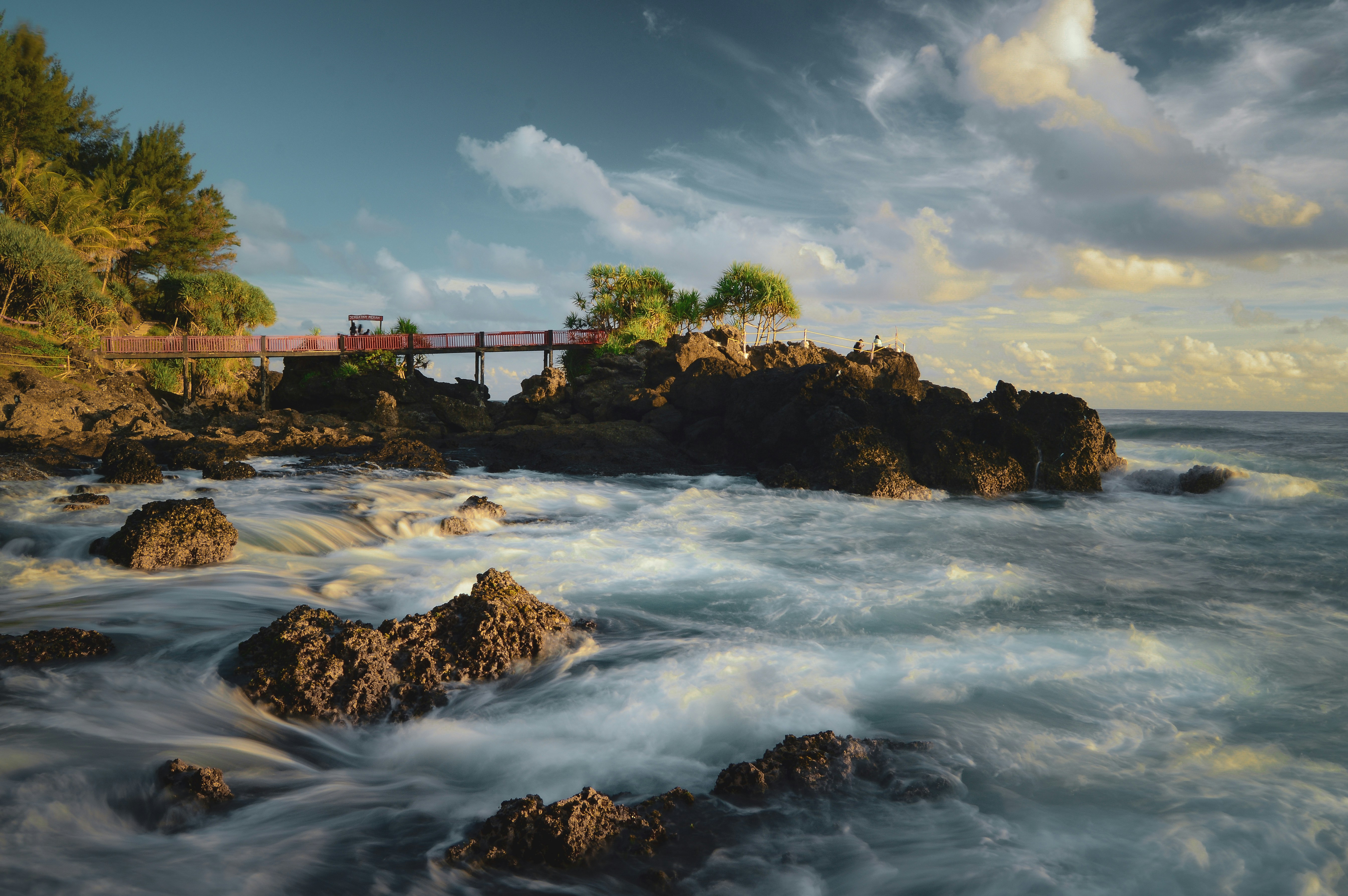 Rugged coastline under a sculpted sky, anchored by a wooden overlook