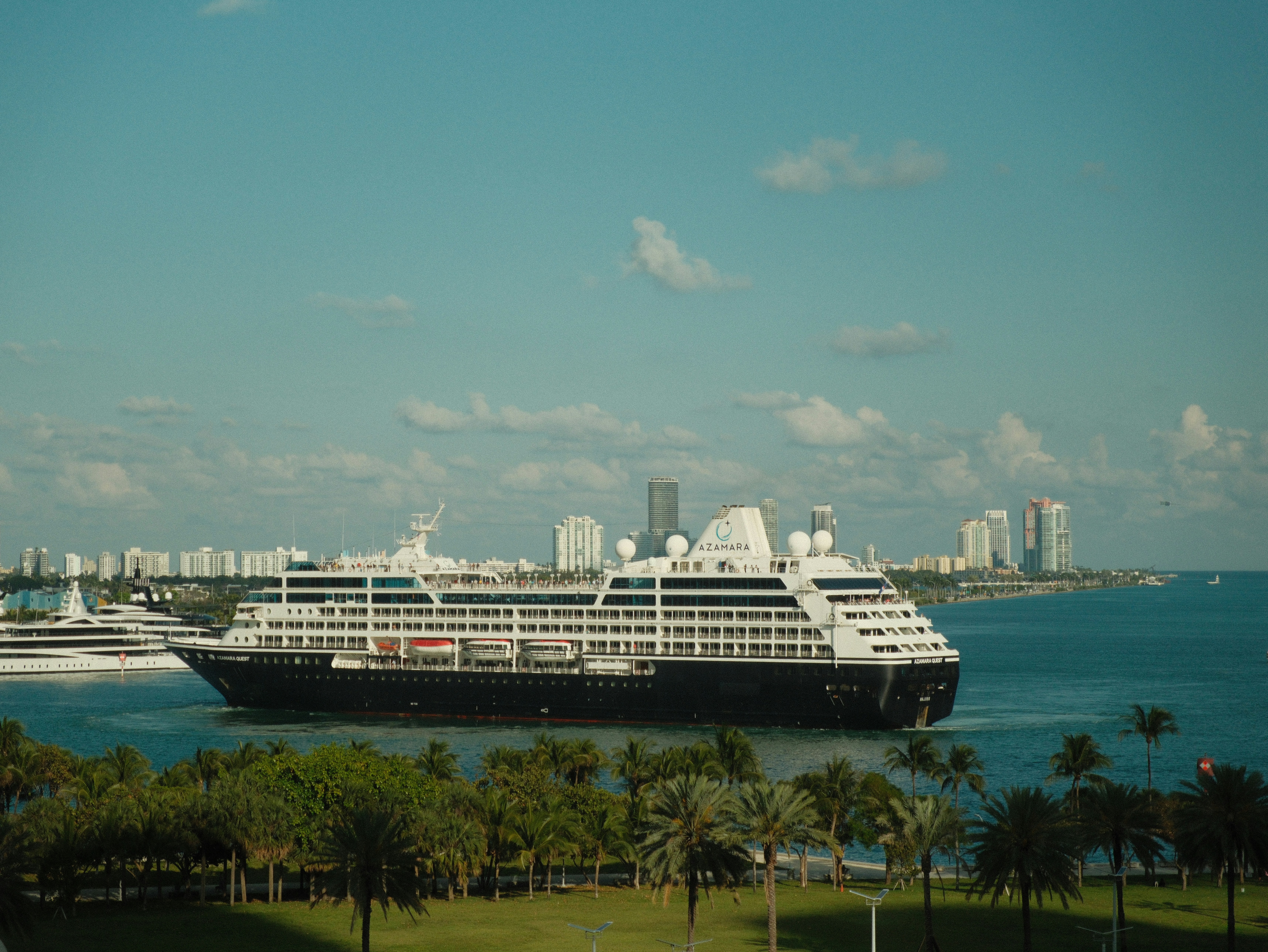 A large cruise ship sailing past a city skyline.