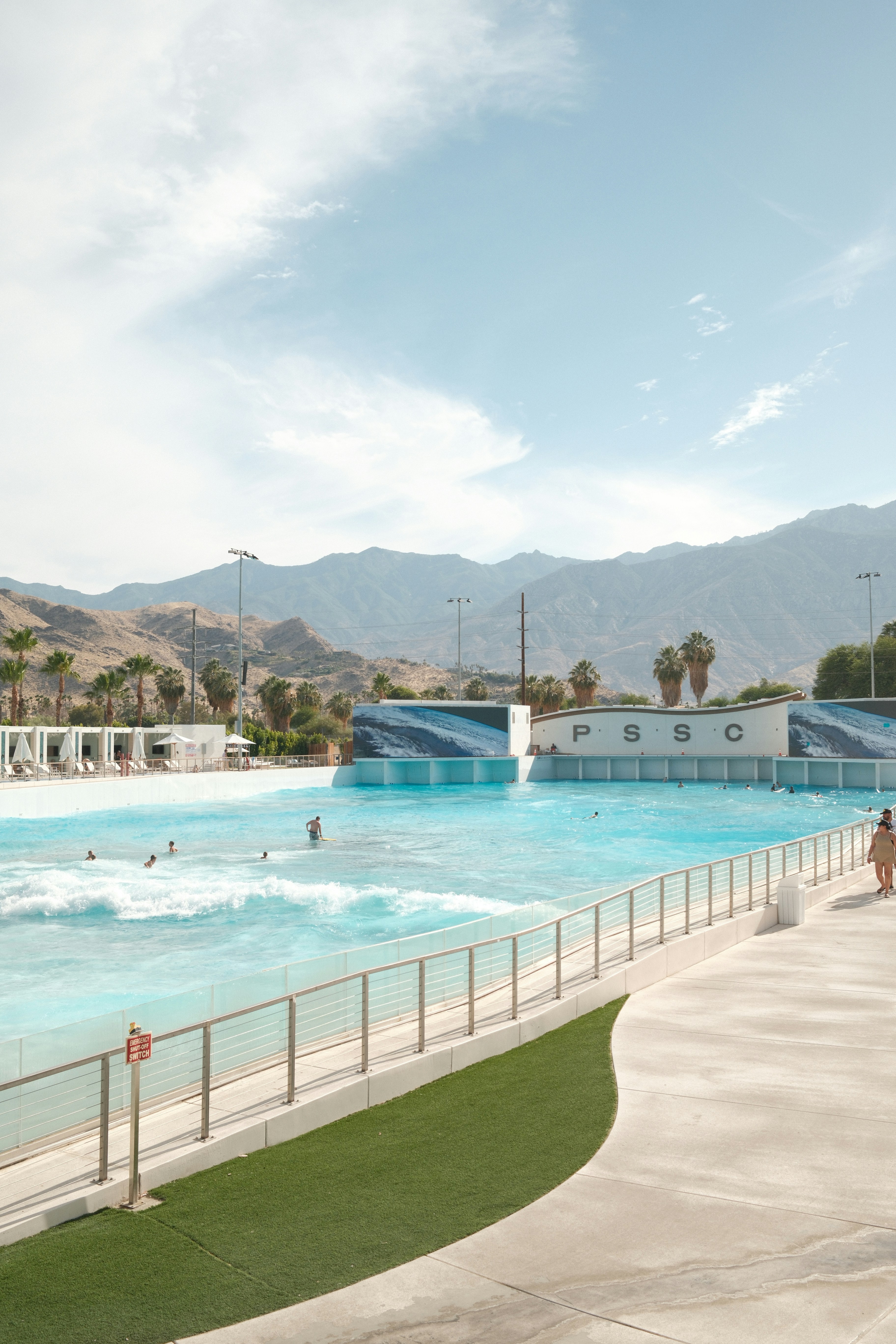A large wave pool with mountains under a blue sky.