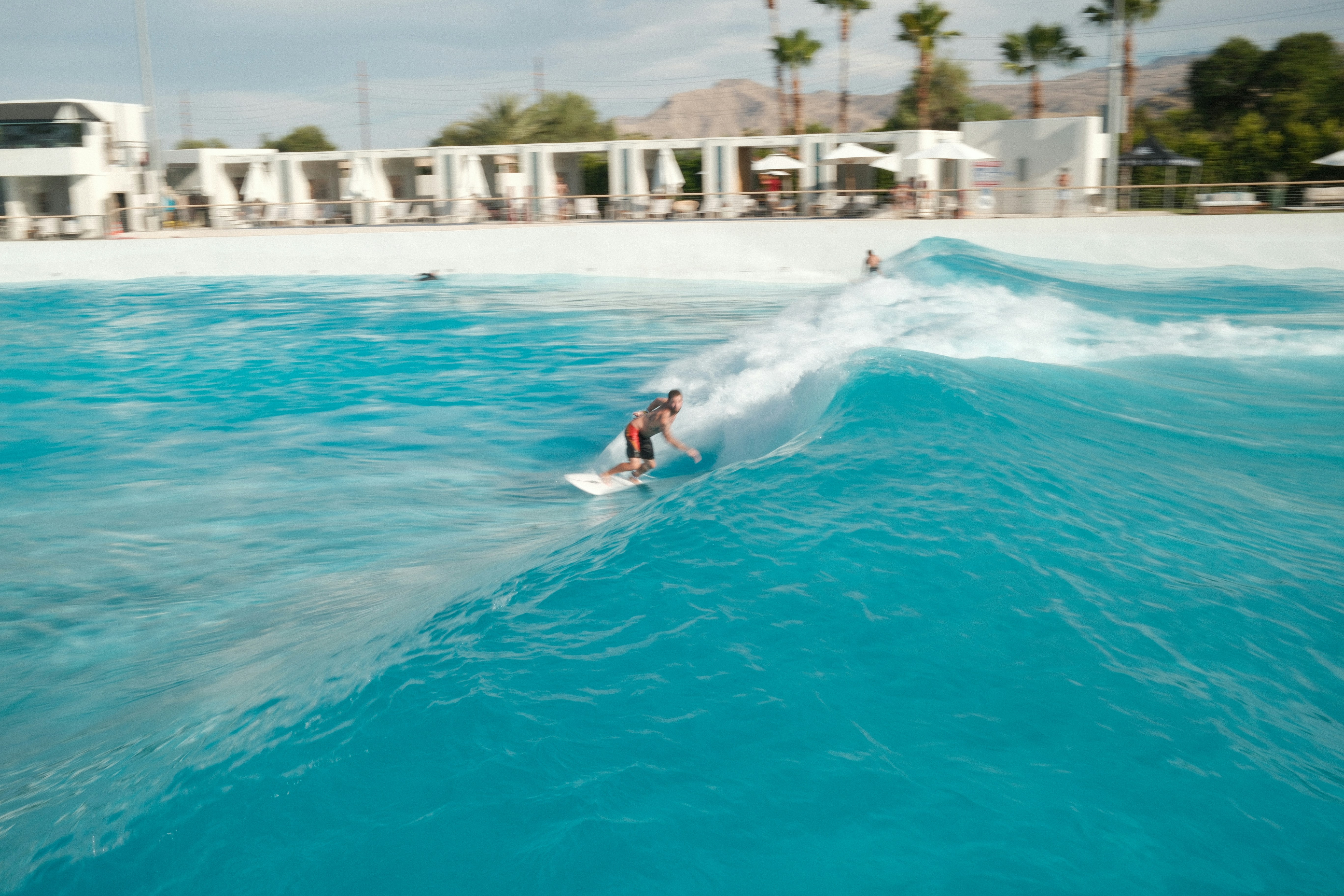 Razor Crest of the Wave: A Surfer Skims the Crest at a Sunlit Poolside Wave