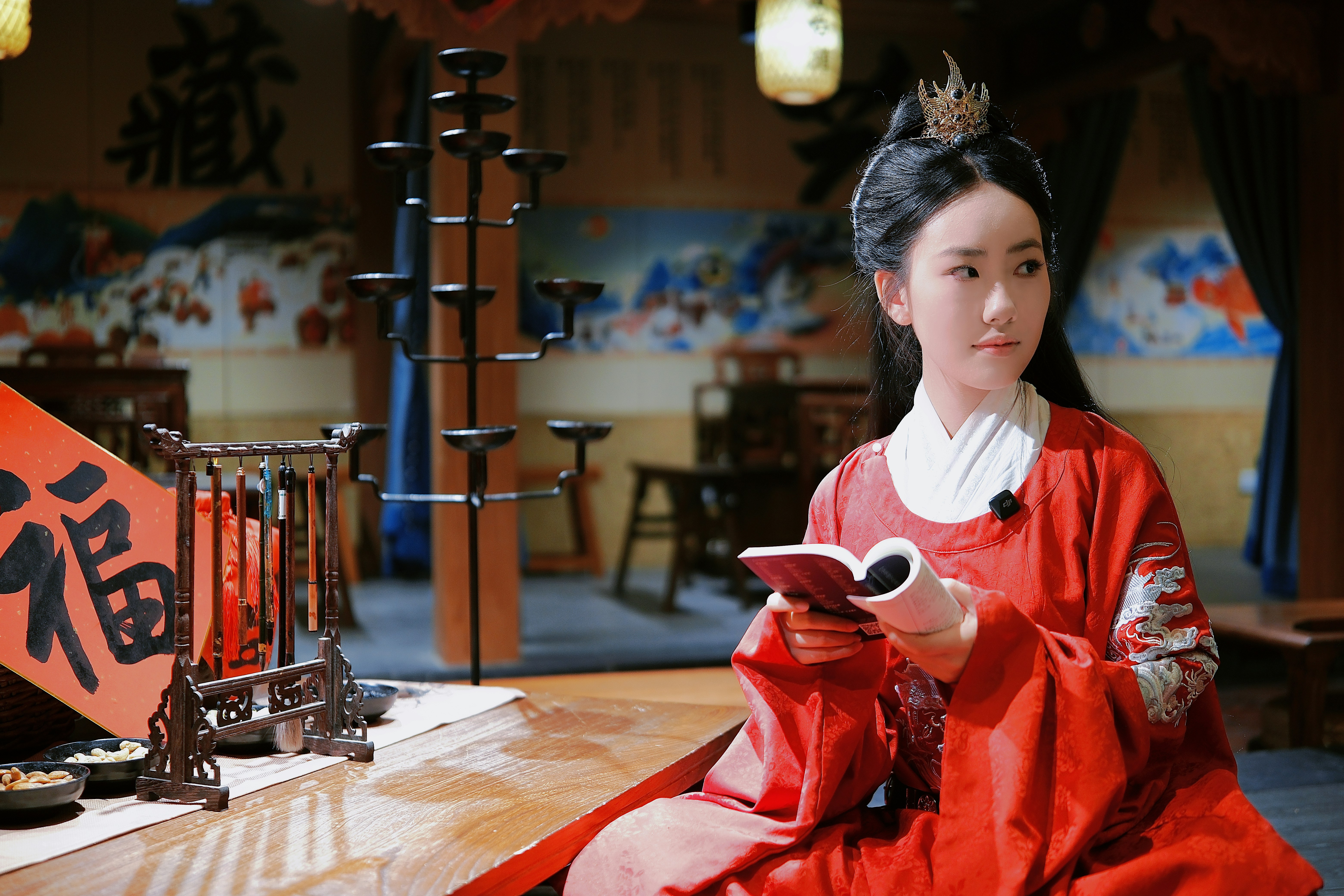 Young chinese woman in traditional red dress holding a book.