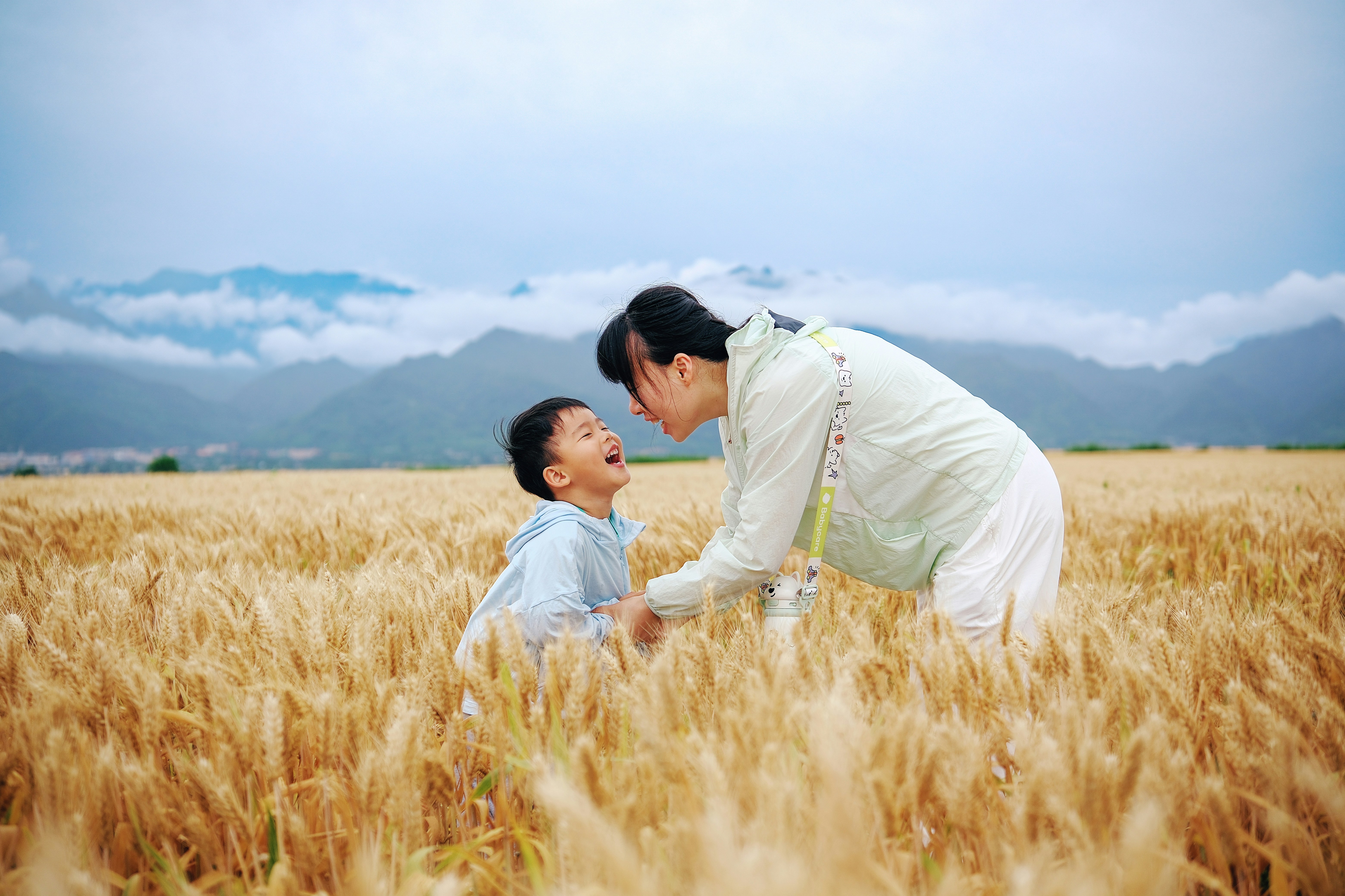 Woman and child having fun in a golden wheat field.