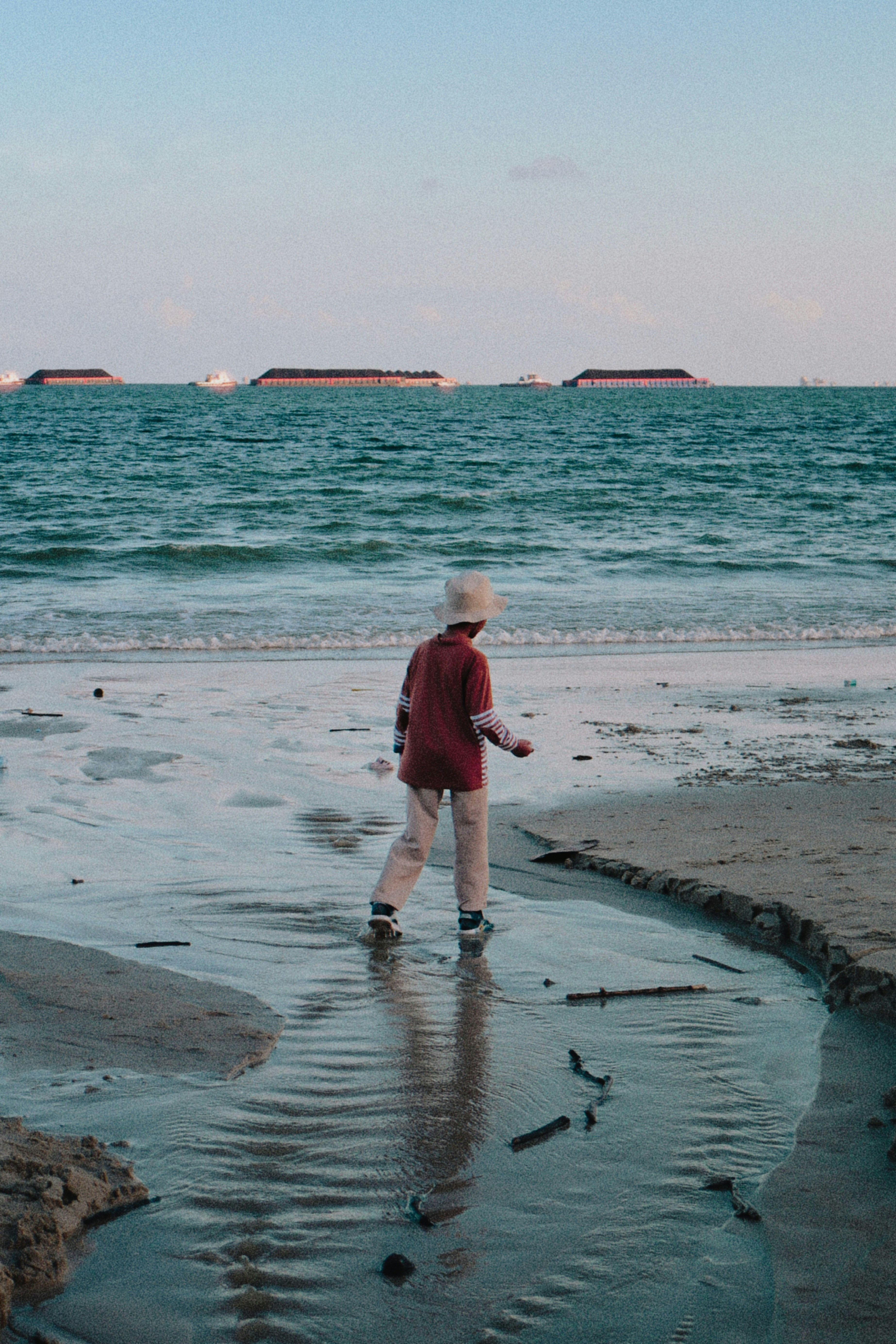Kid in terracotta red playing at the beach