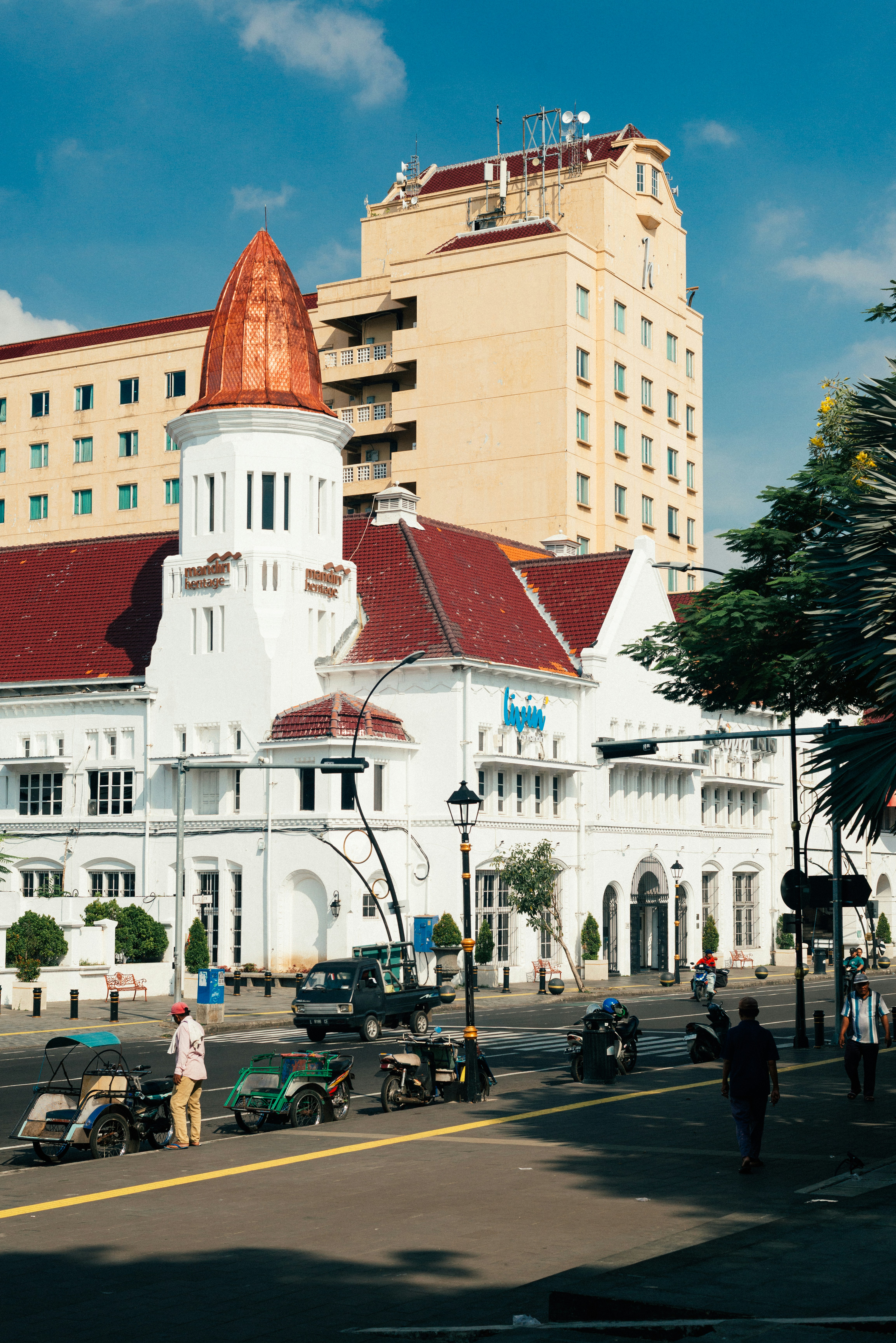 White Colonial building with copper-topped tower against a city backdrop