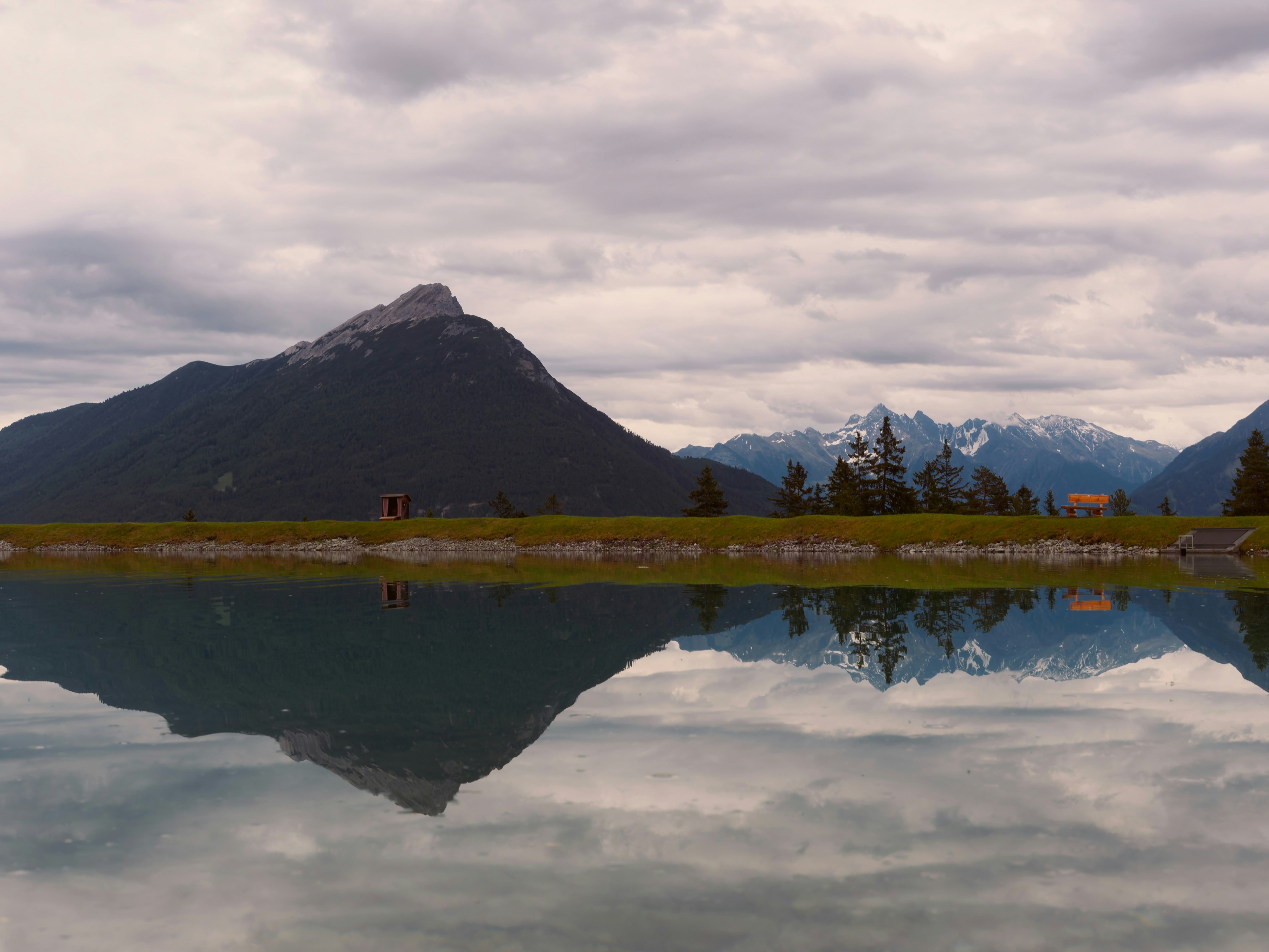 Silent Mountain Mirror: Snow-Capped Peaks Reflected in Alpine Lake Under Soft Clouds