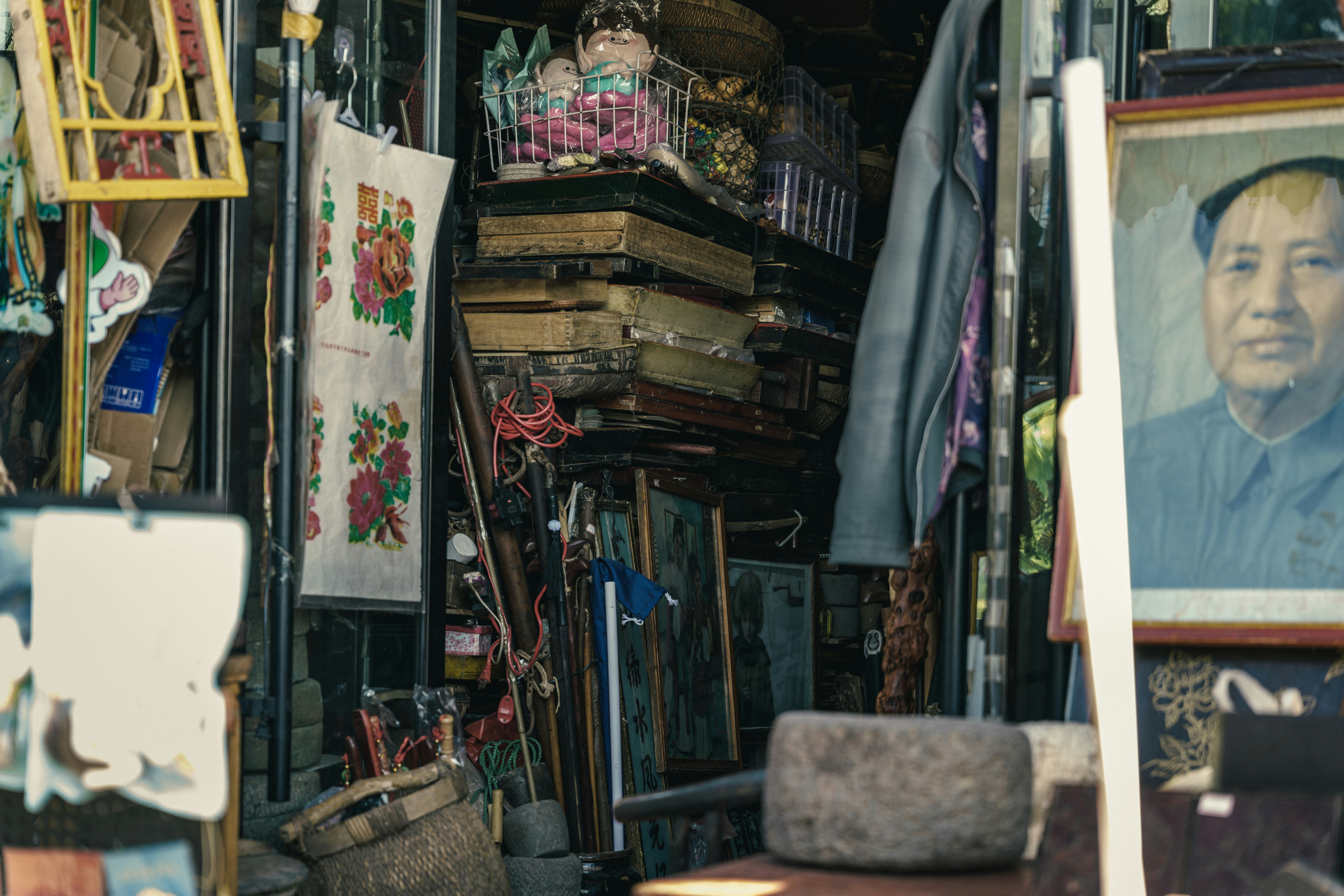 Cluttered antique shop with a framed portrait of mao zedong.
