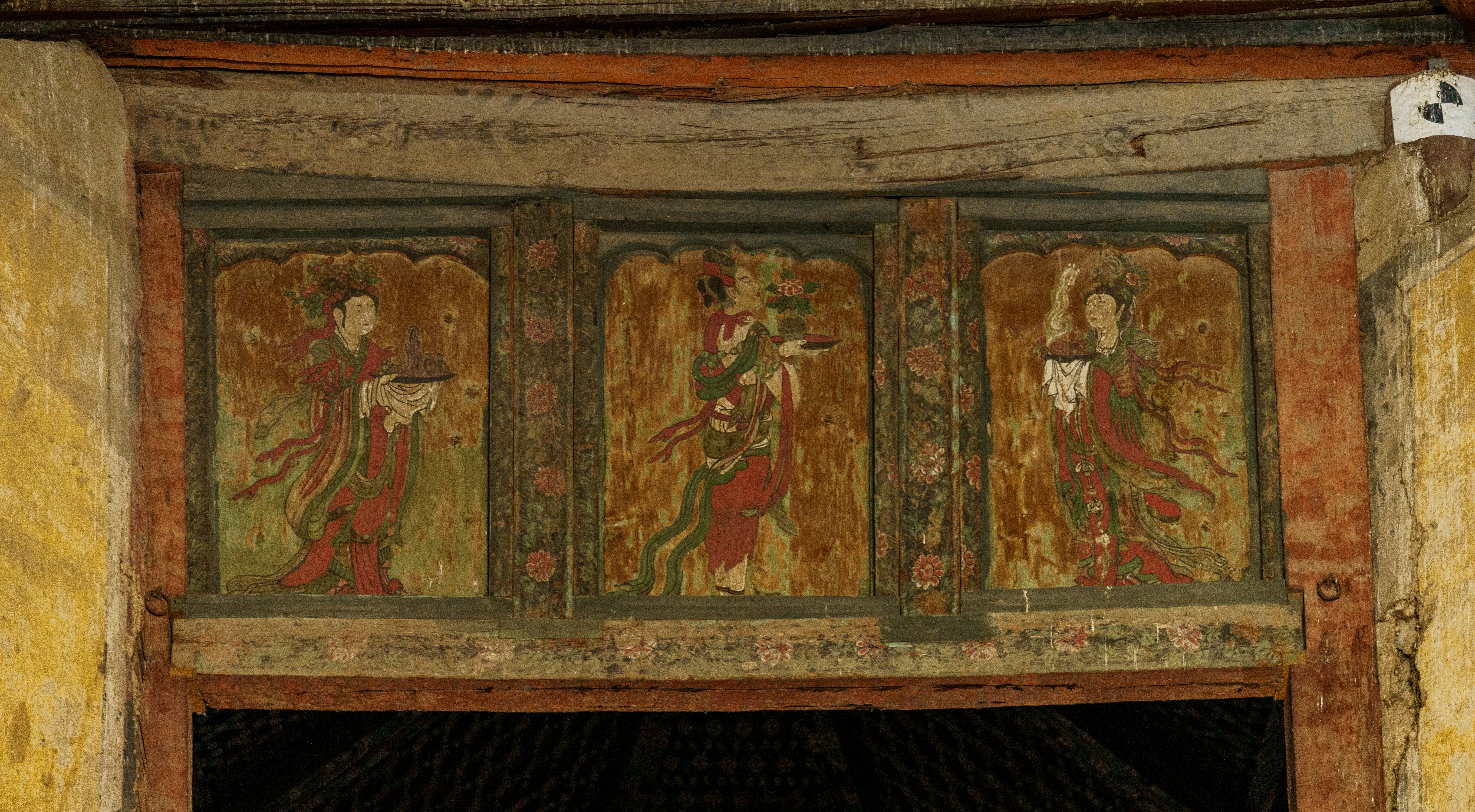 Ancient Doorway Frieze: Weathered Sacred Figures Above a Dark Entrance