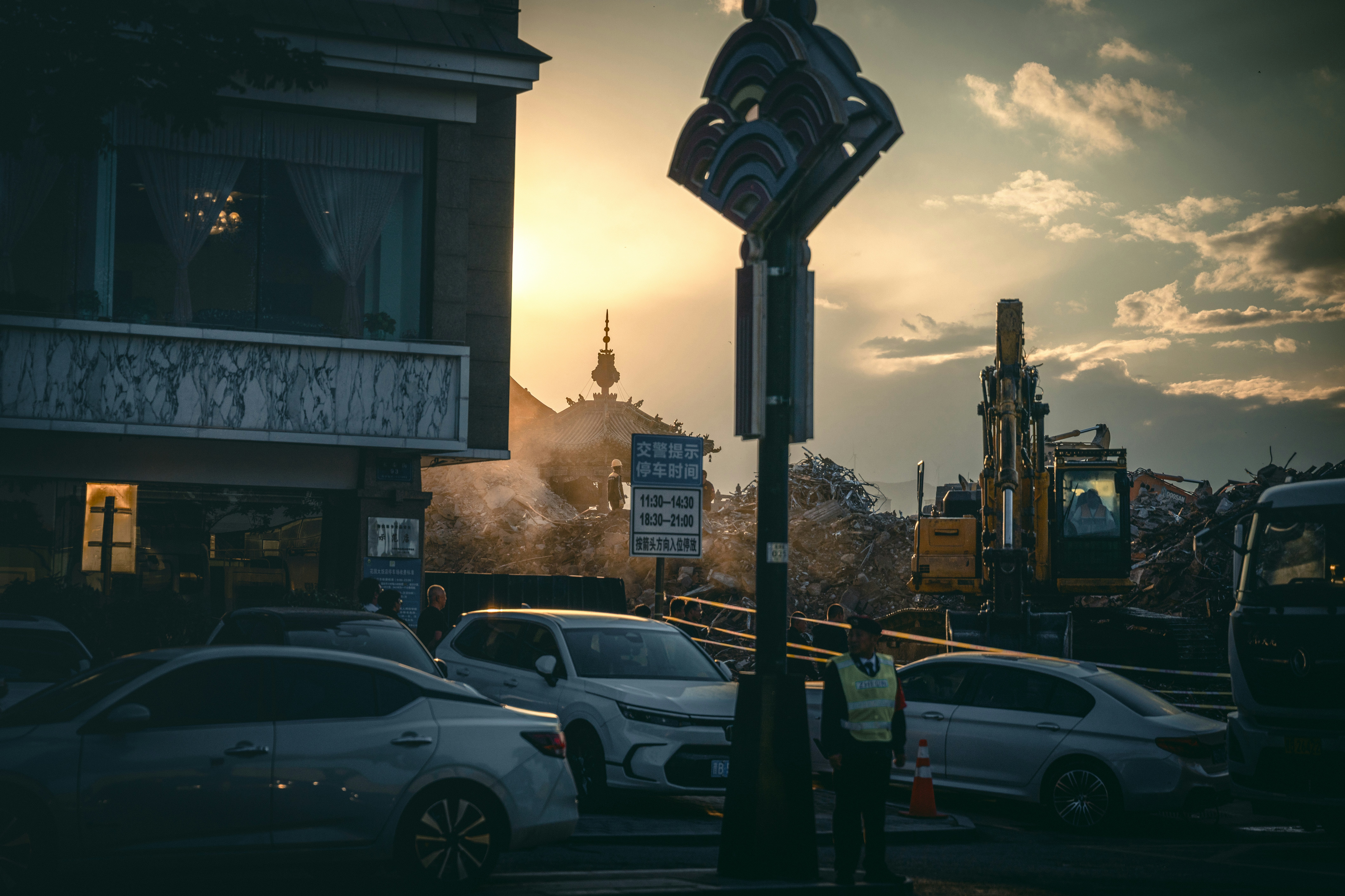 City street with cars, buildings, and construction at sunset.
