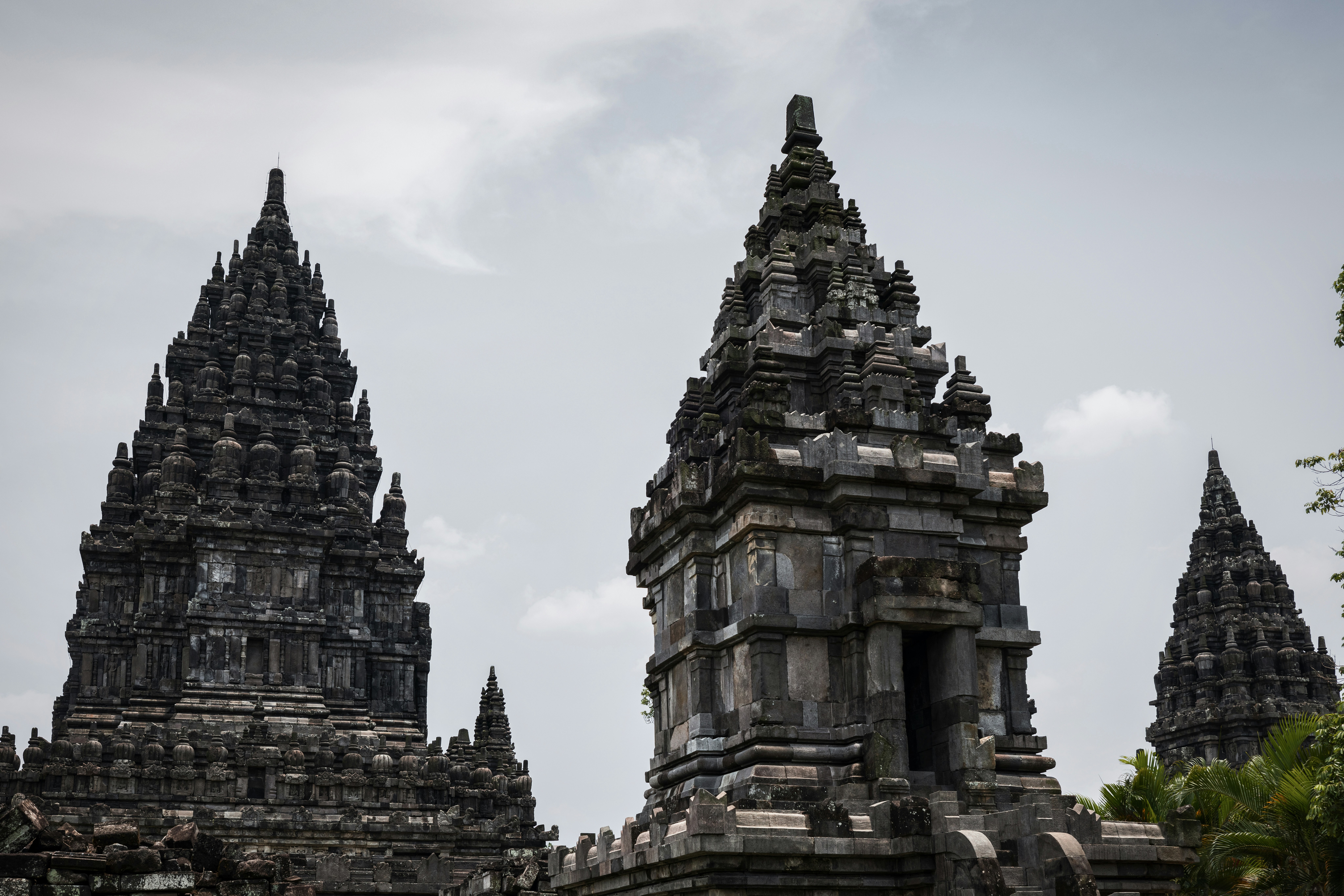 Ancient stone temples with intricate carvings under a cloudy sky.