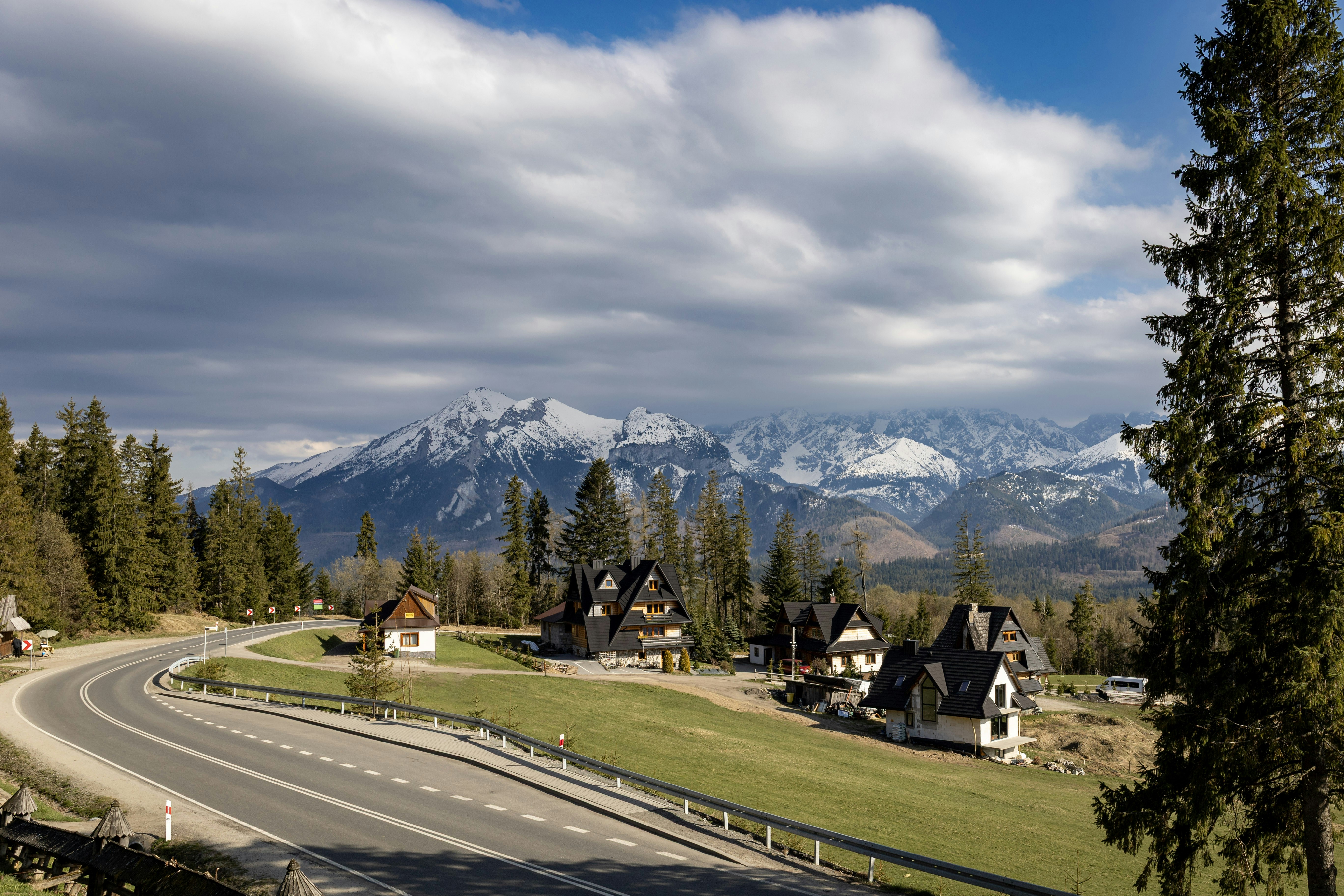 alpine village along a winding road with snow-capped peaks