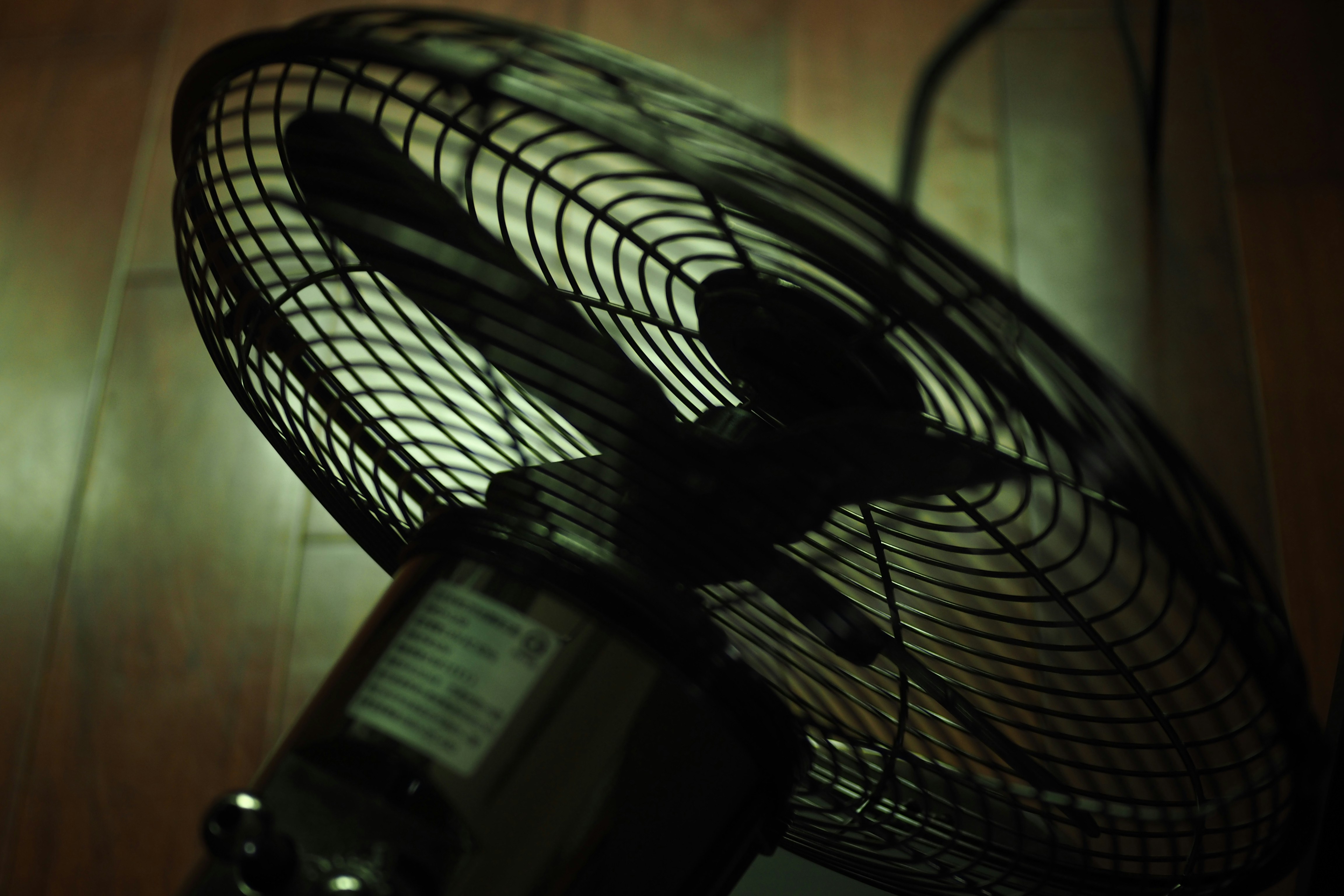 A dark electric fan with a protective grille.