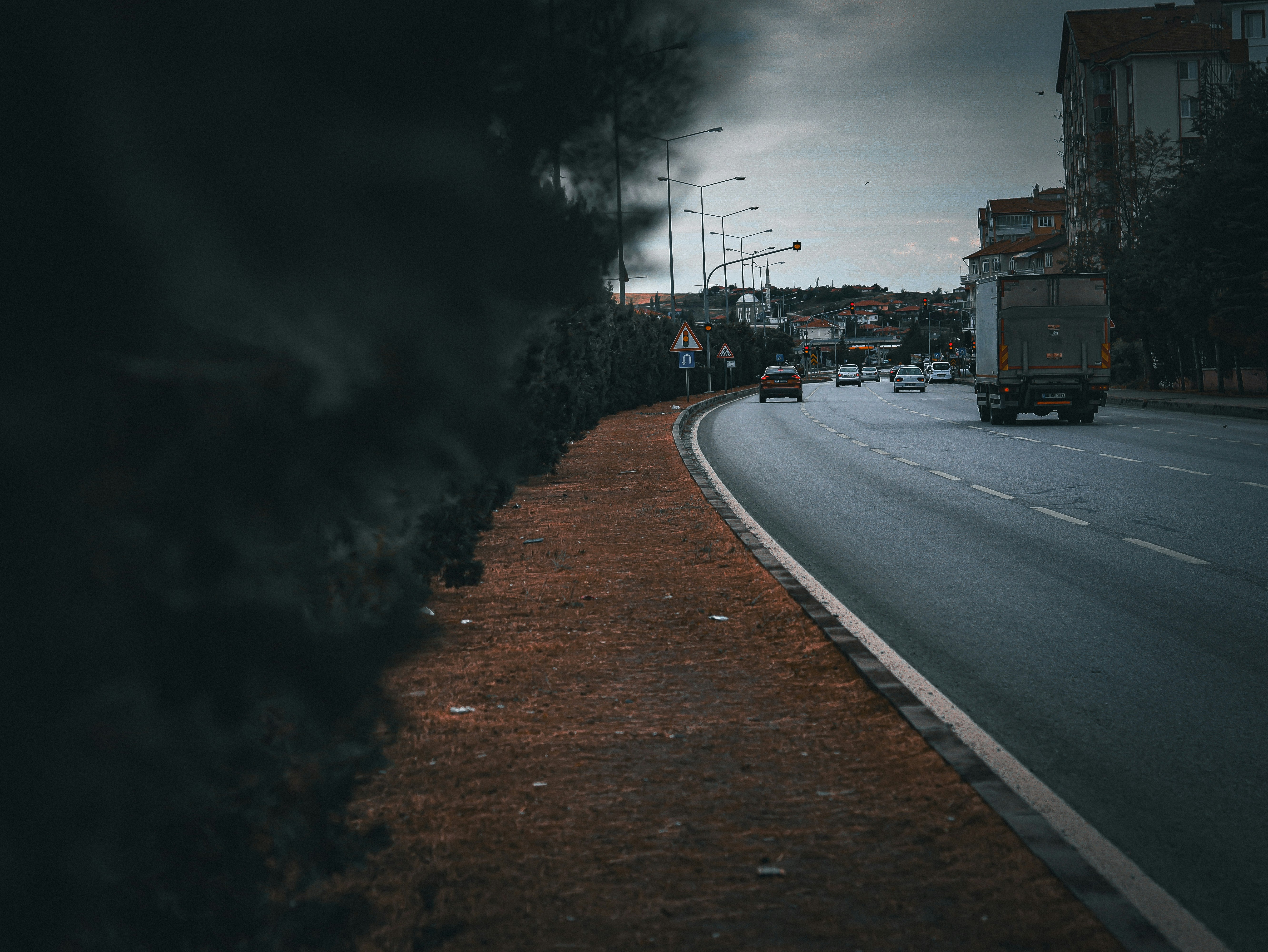 Mid-Urban Curve: Cars in Transit Beneath a Moody Sky