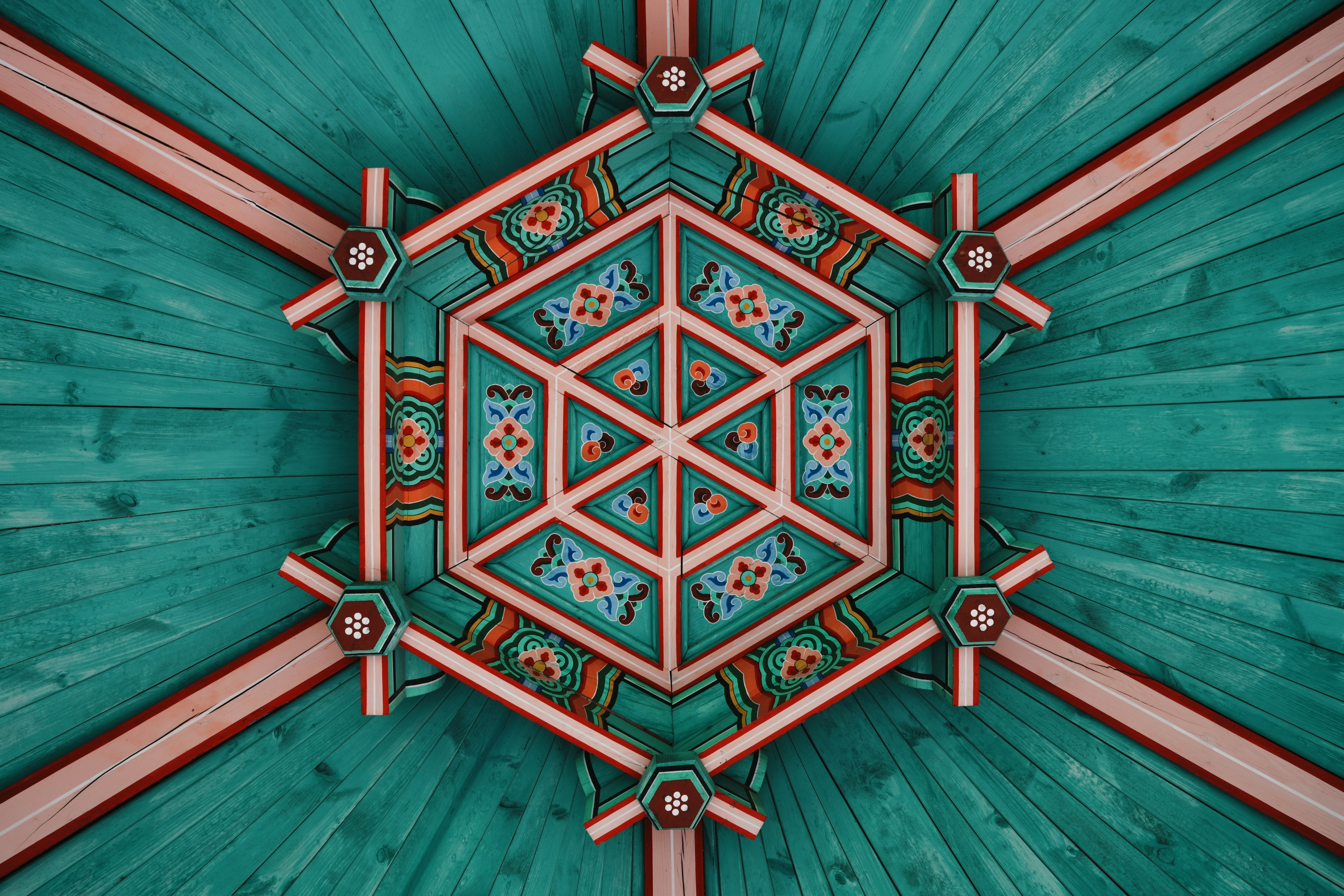 Intricate hexagonal pattern on a traditional teal and red ceiling.