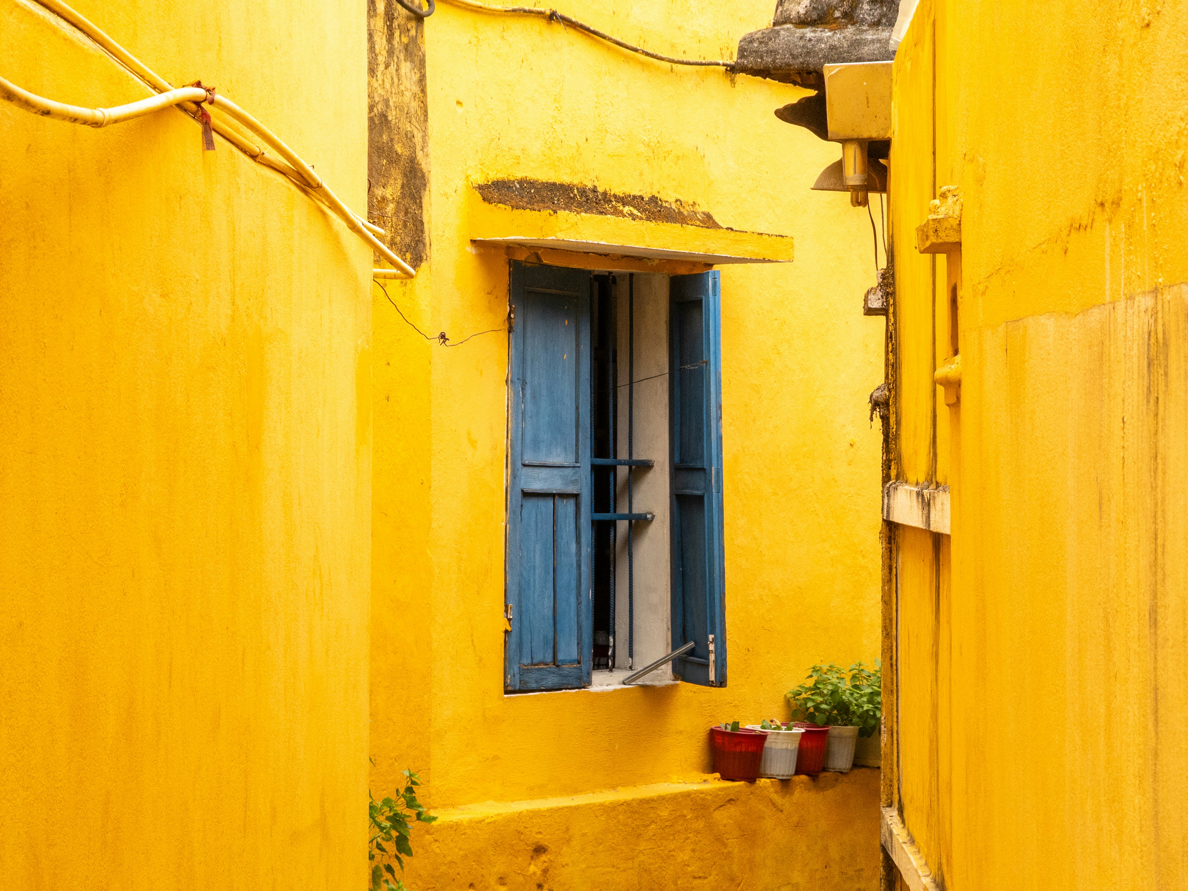 Sunlit Yellow Alleyway with Aged Blue Window