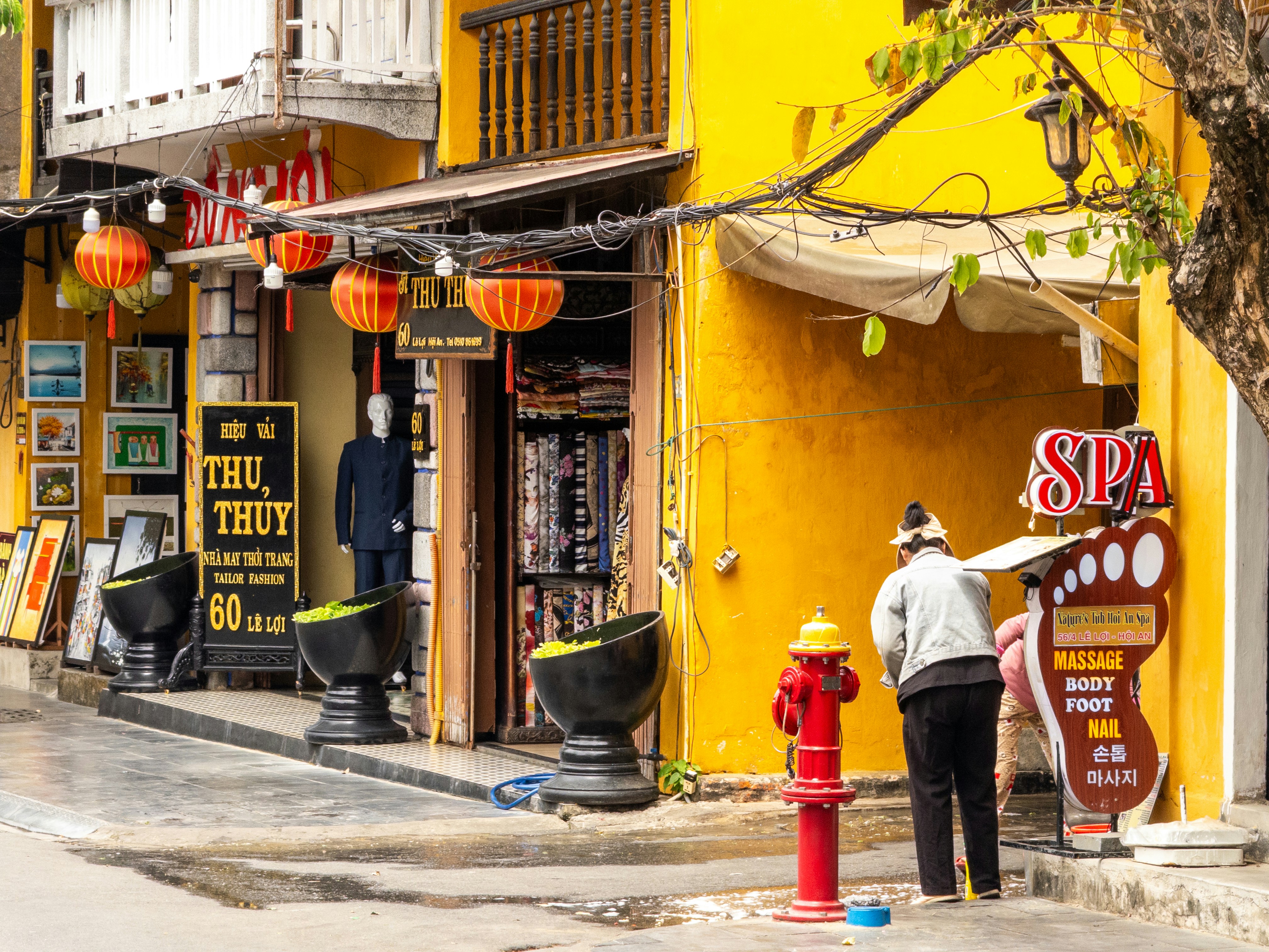 Sunlit Lane in Vibrant Hue: Shopfronts and a Worker at the Edge