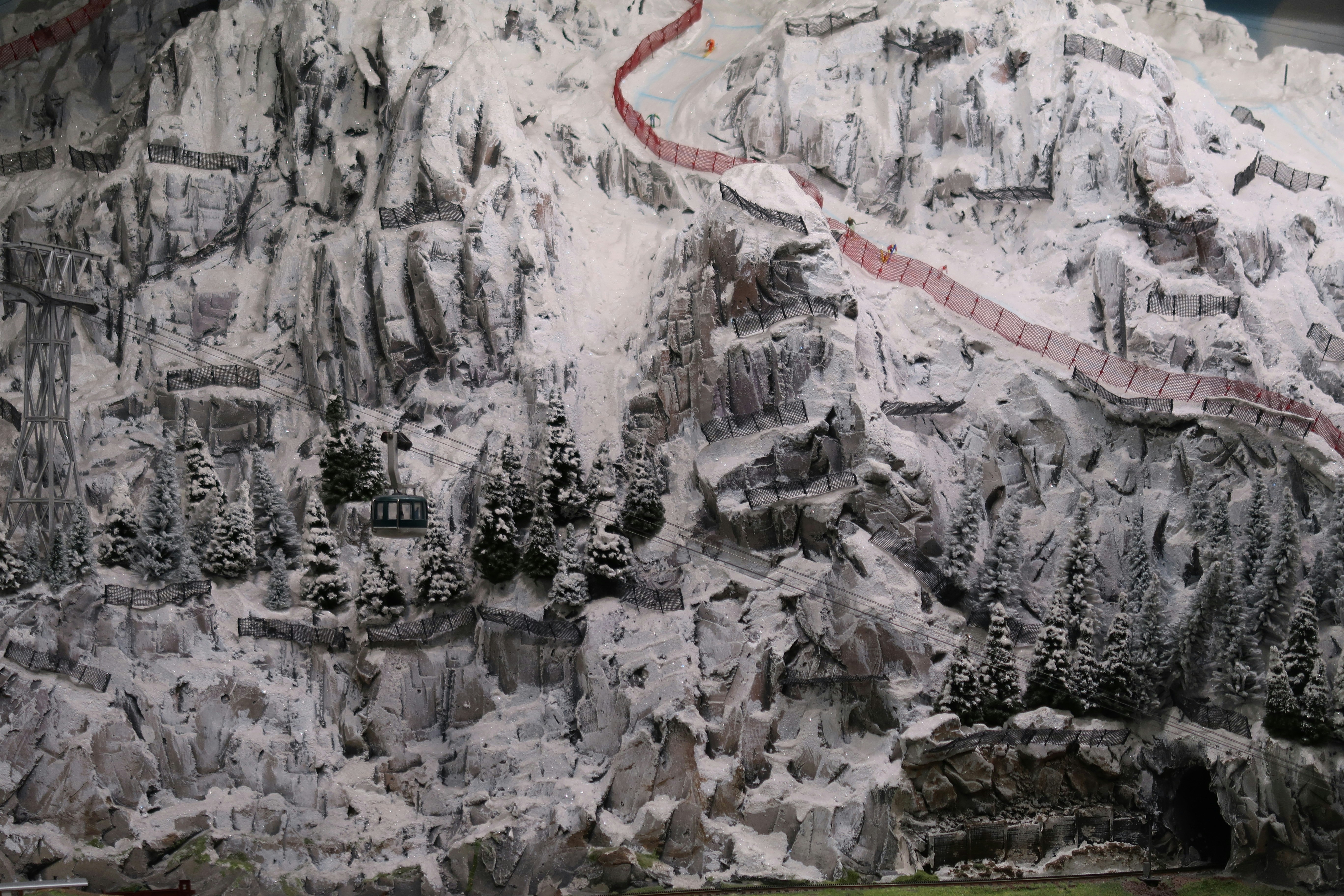 Snow-clad cliffside with winding red safety barrier along a mountain path