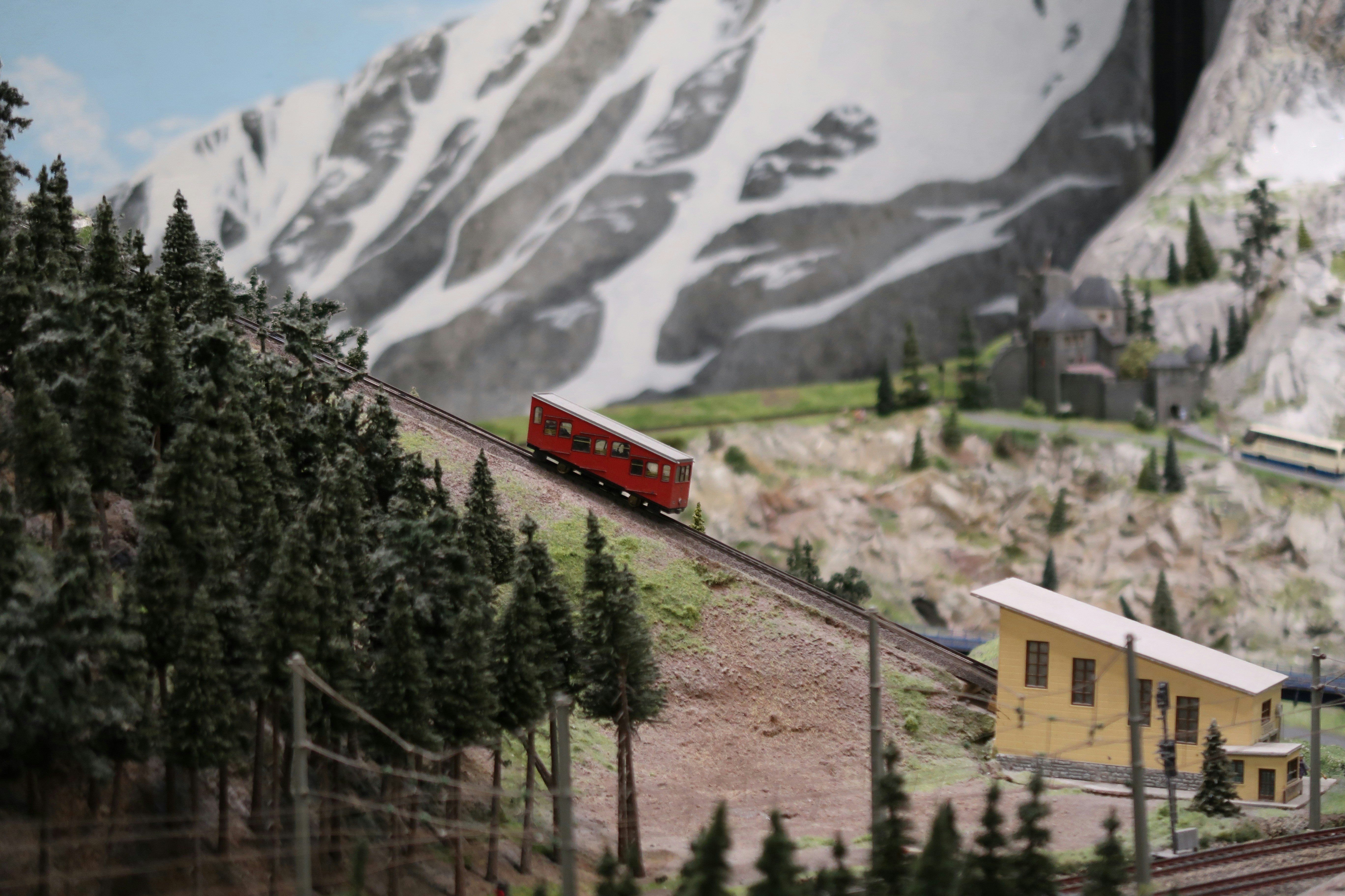 Red Narrow-Gauge Car on a Mountain Train Through a Miniature Alpine Landscape
