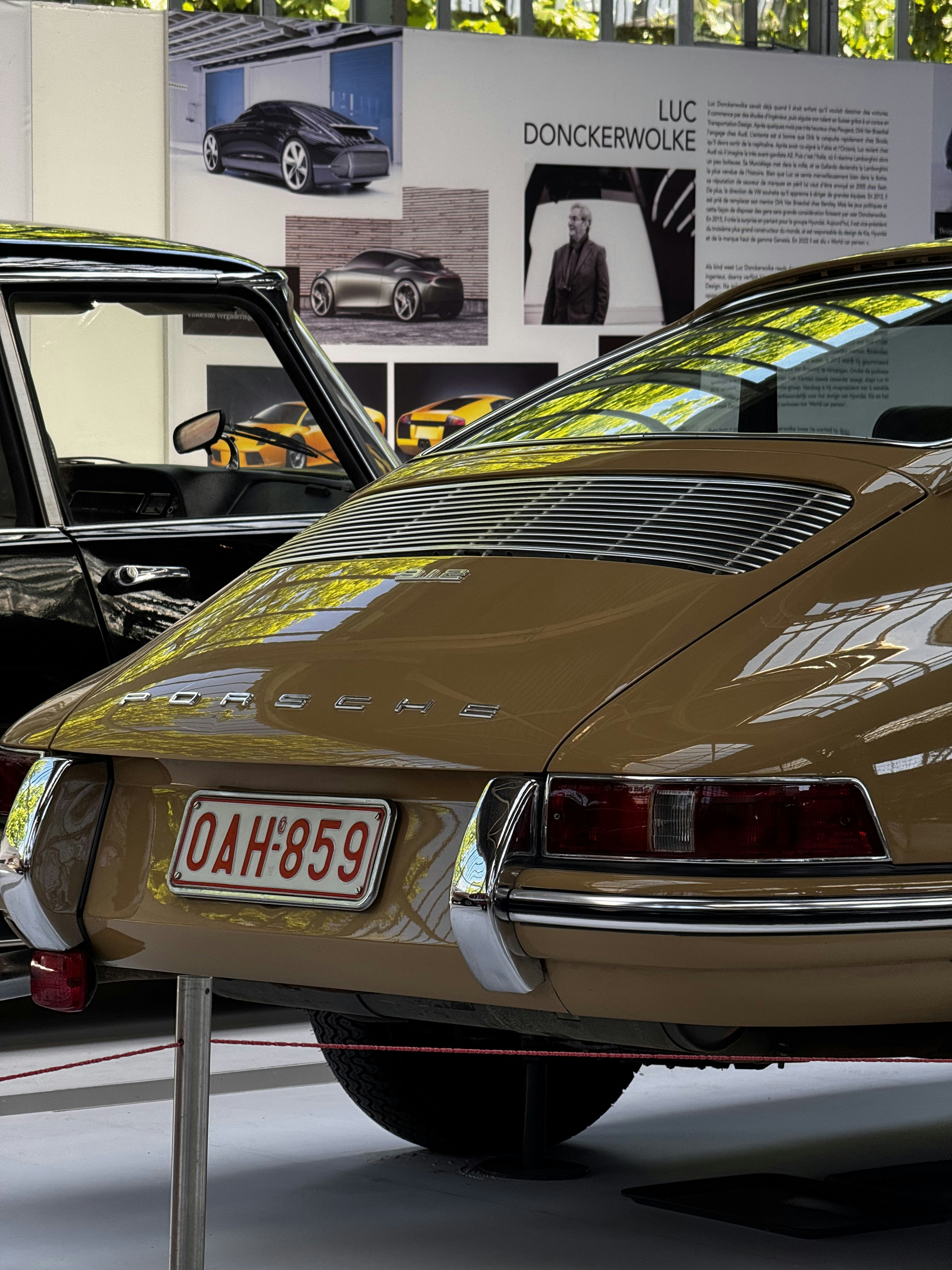 Golden Porsche at a Car Exhibit: Reflections, Retro Lines, and Exhibited History