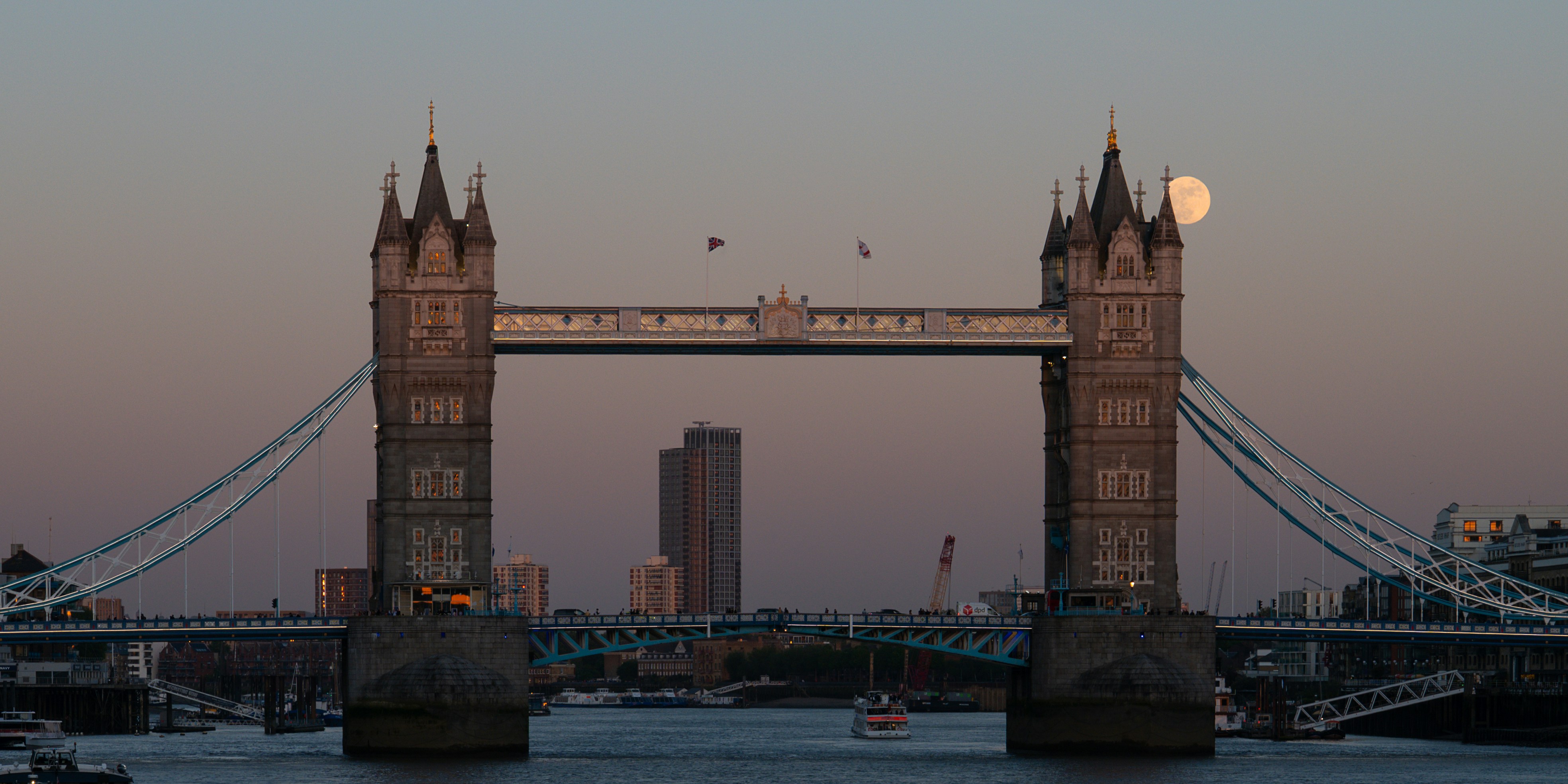 Full moon rising over tower bridge at twilight.