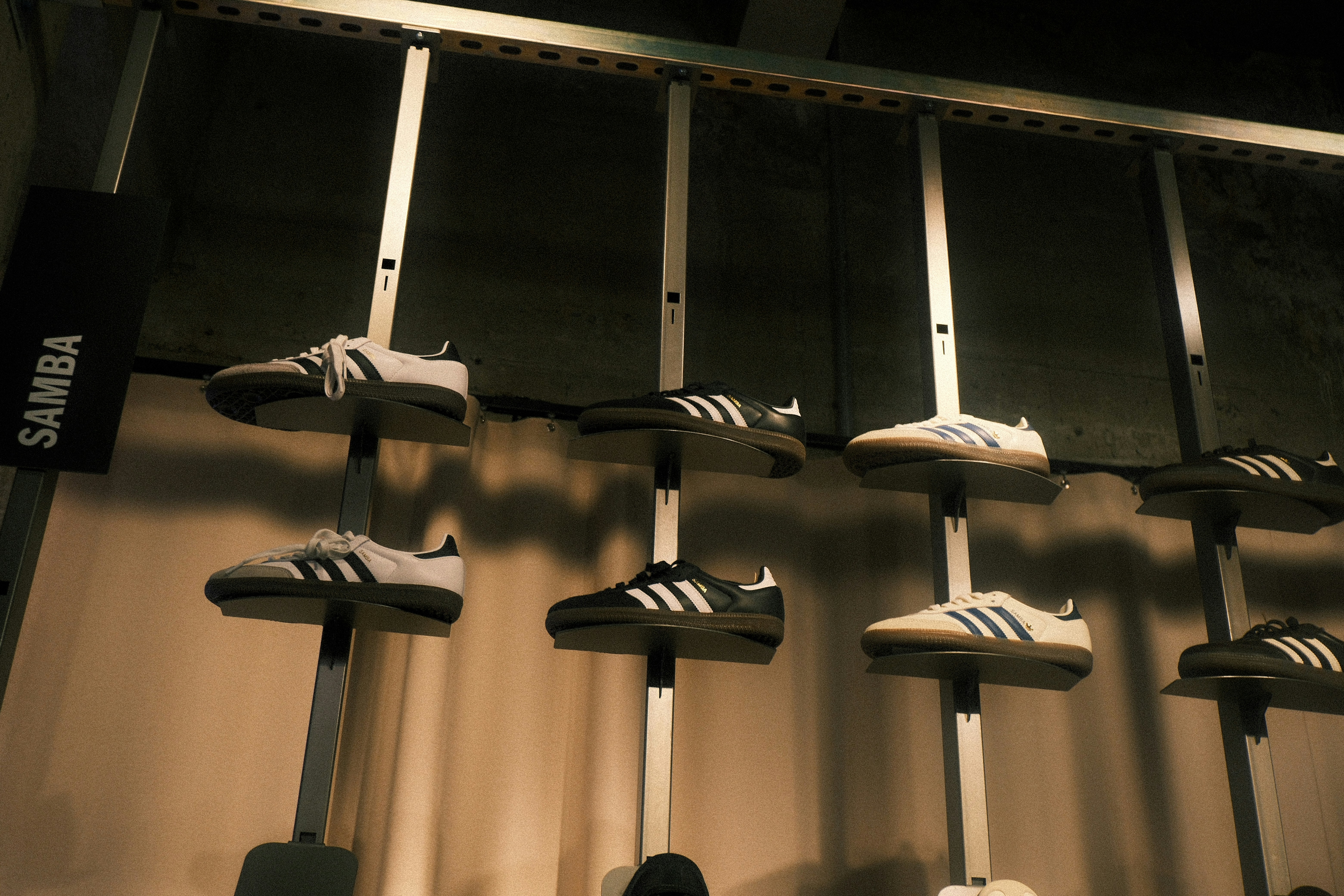 Adidas samba sneakers displayed on a shoe store wall.