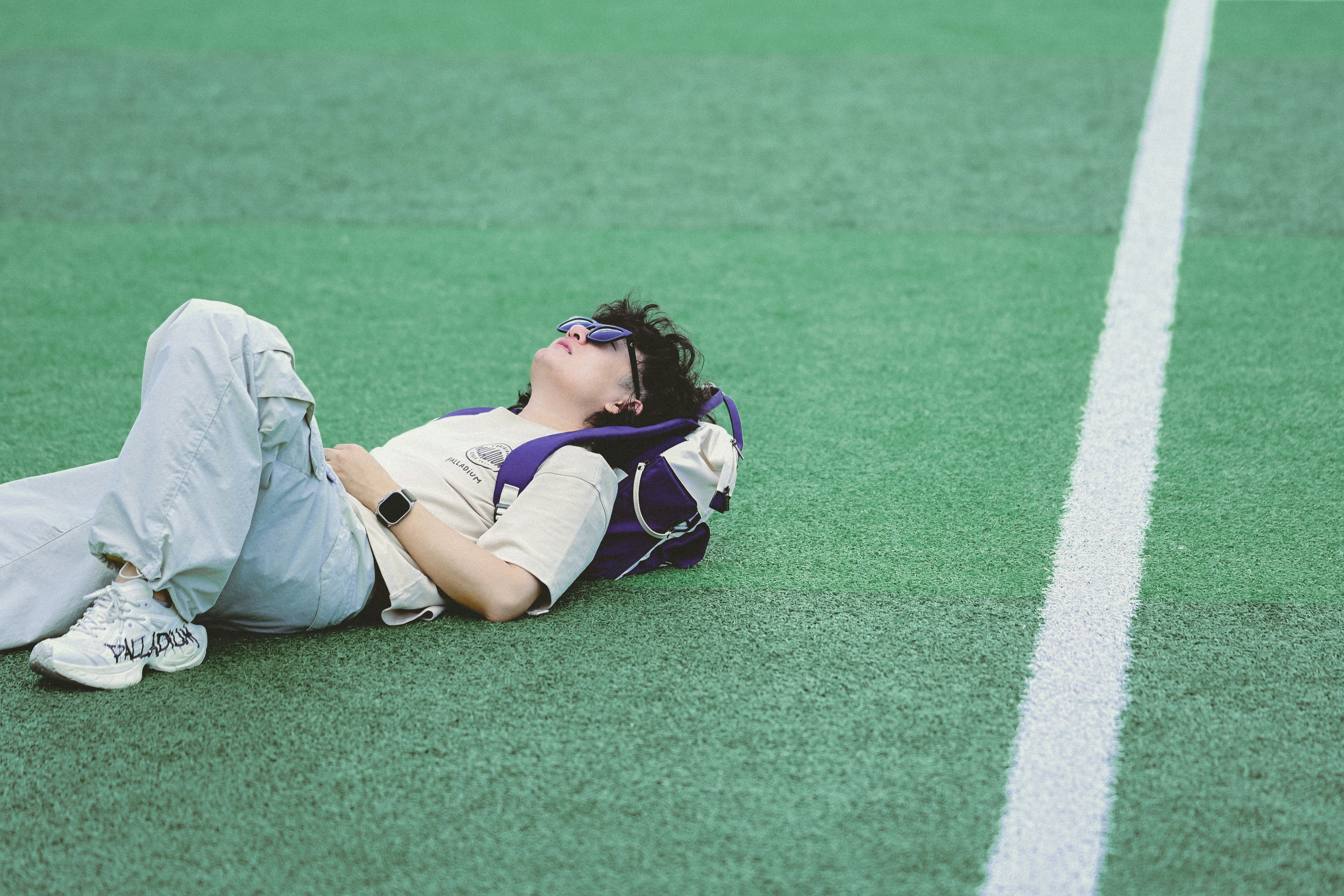 Person in sunglasses relaxing on green artificial turf.