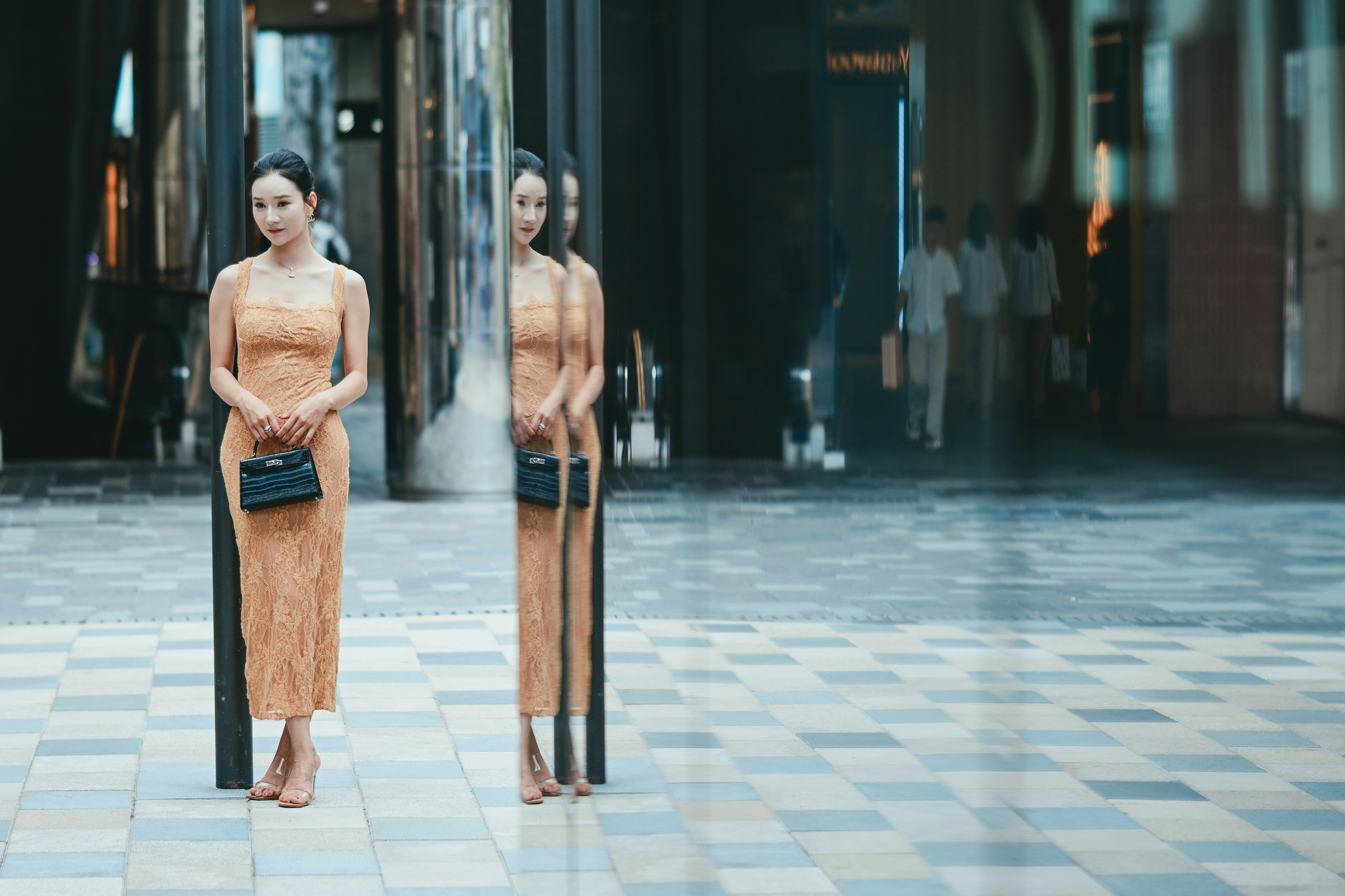Woman in peach dress reflected in a distorted mirror.