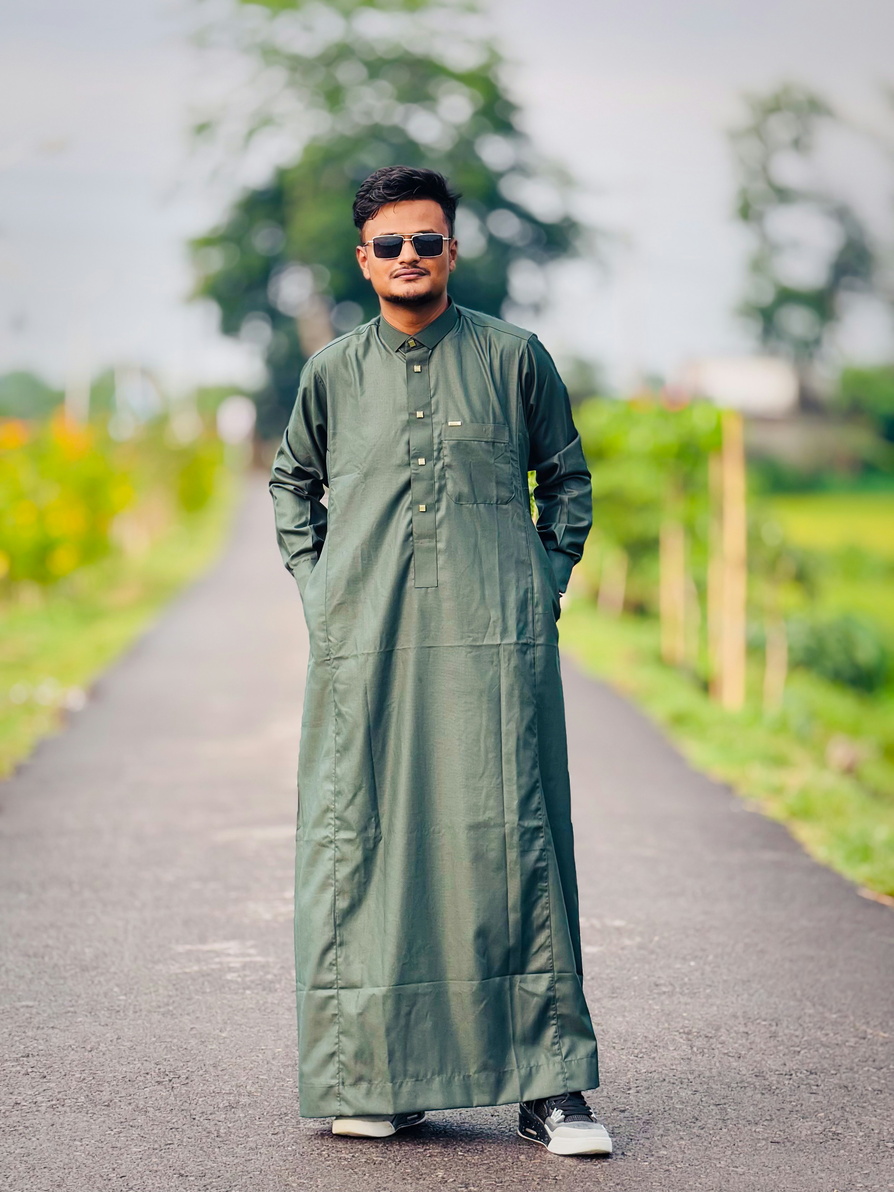 Man wearing a long green robe and sunglasses outdoors.